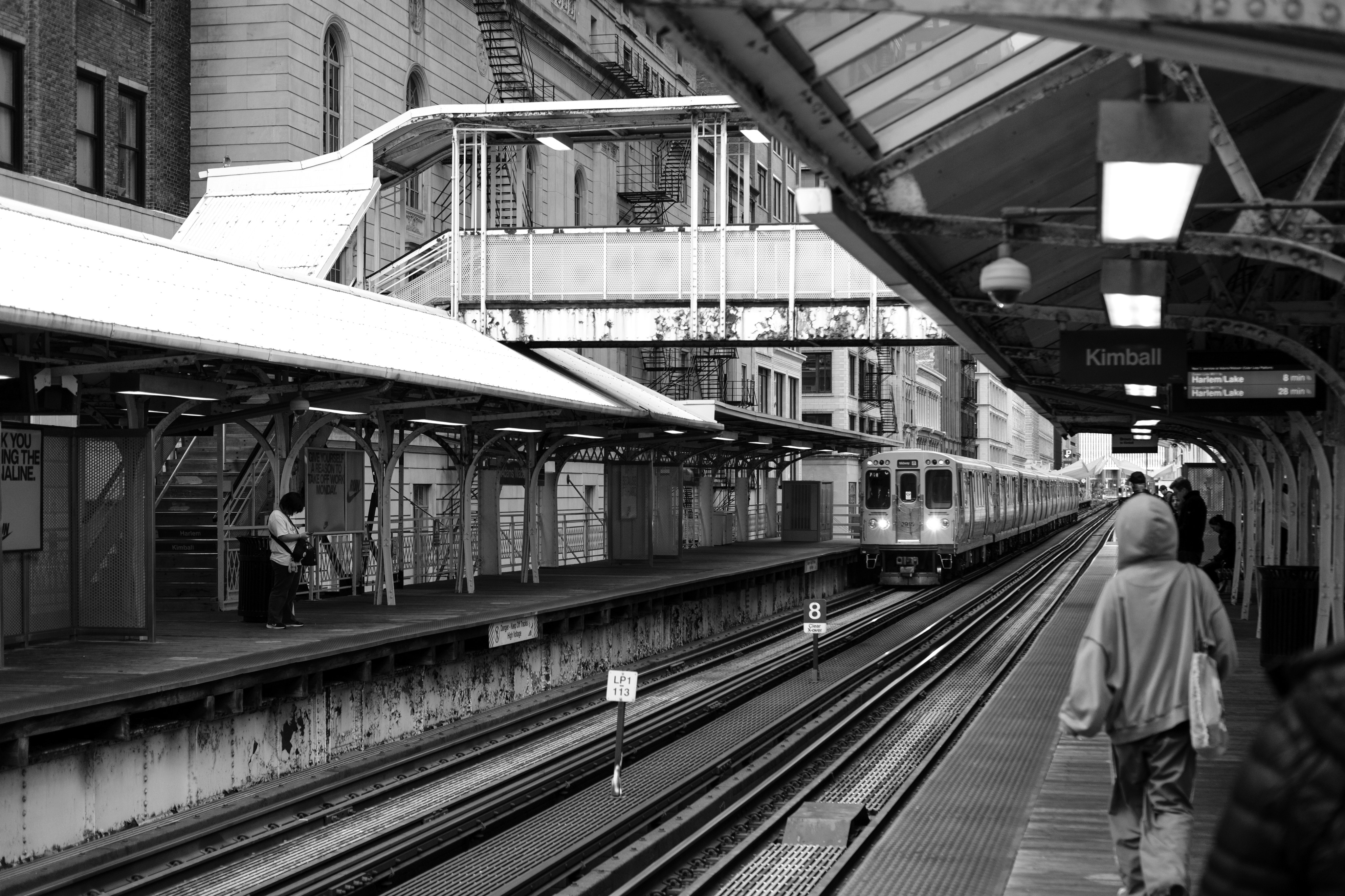 Platform vignette: a lone commuter along a monochrome city railway