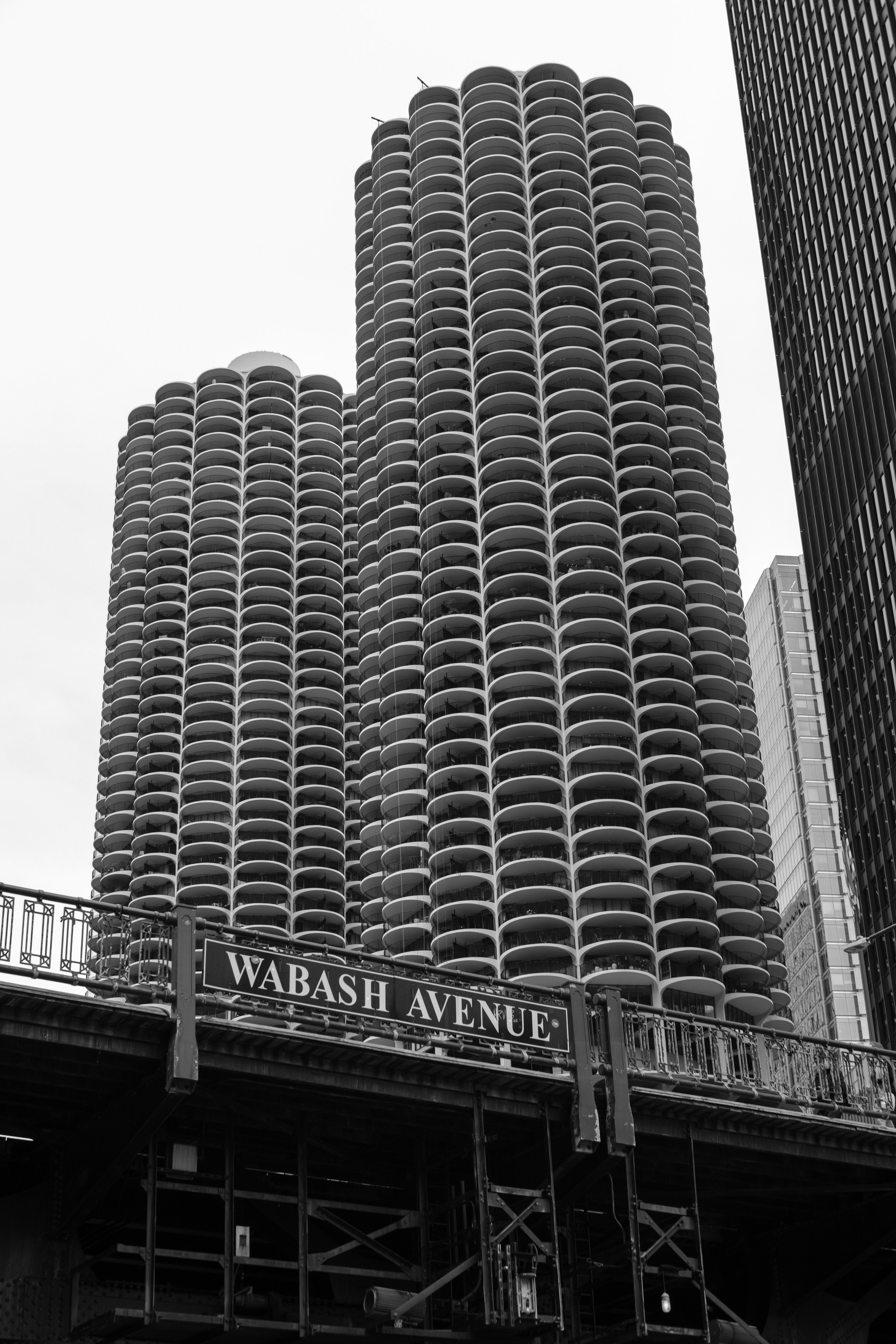 Two cylindrical high-rise buildings behind a wabash avenue bridge.