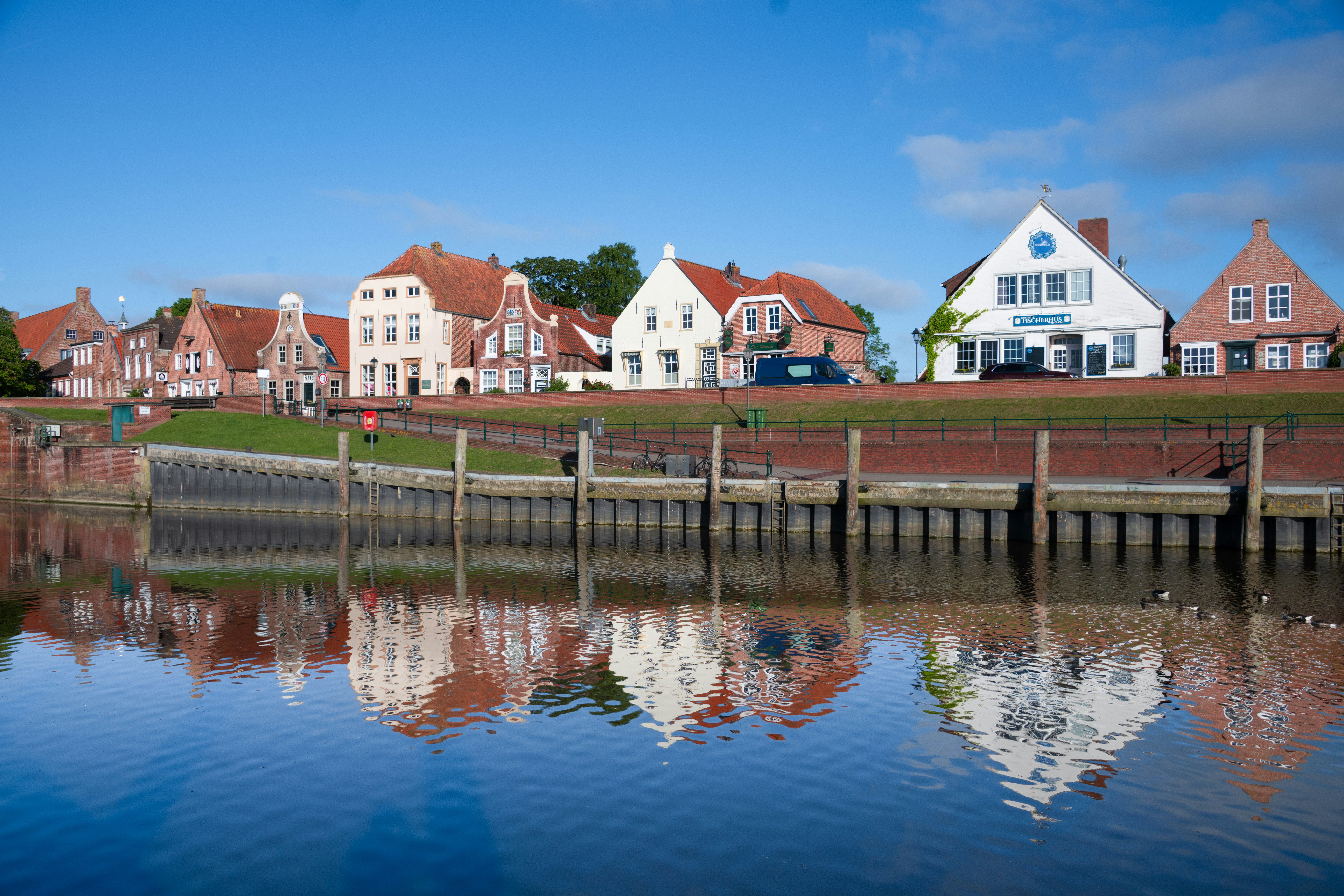 Row of seaside cottages reflected in calm harbor water