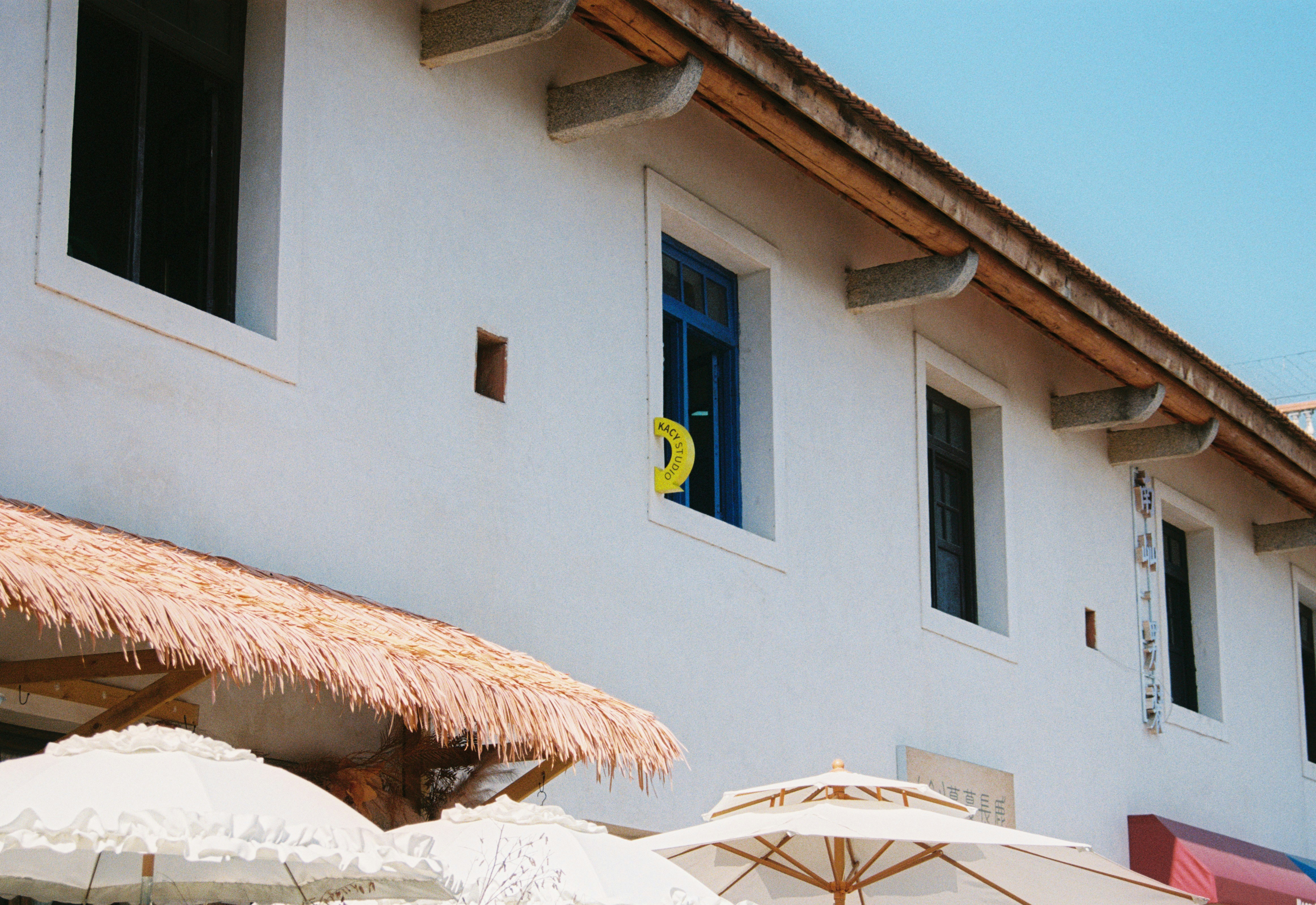 Boutique Coastal Inn: Whitewashed Facade and Cafe Umbrellas
