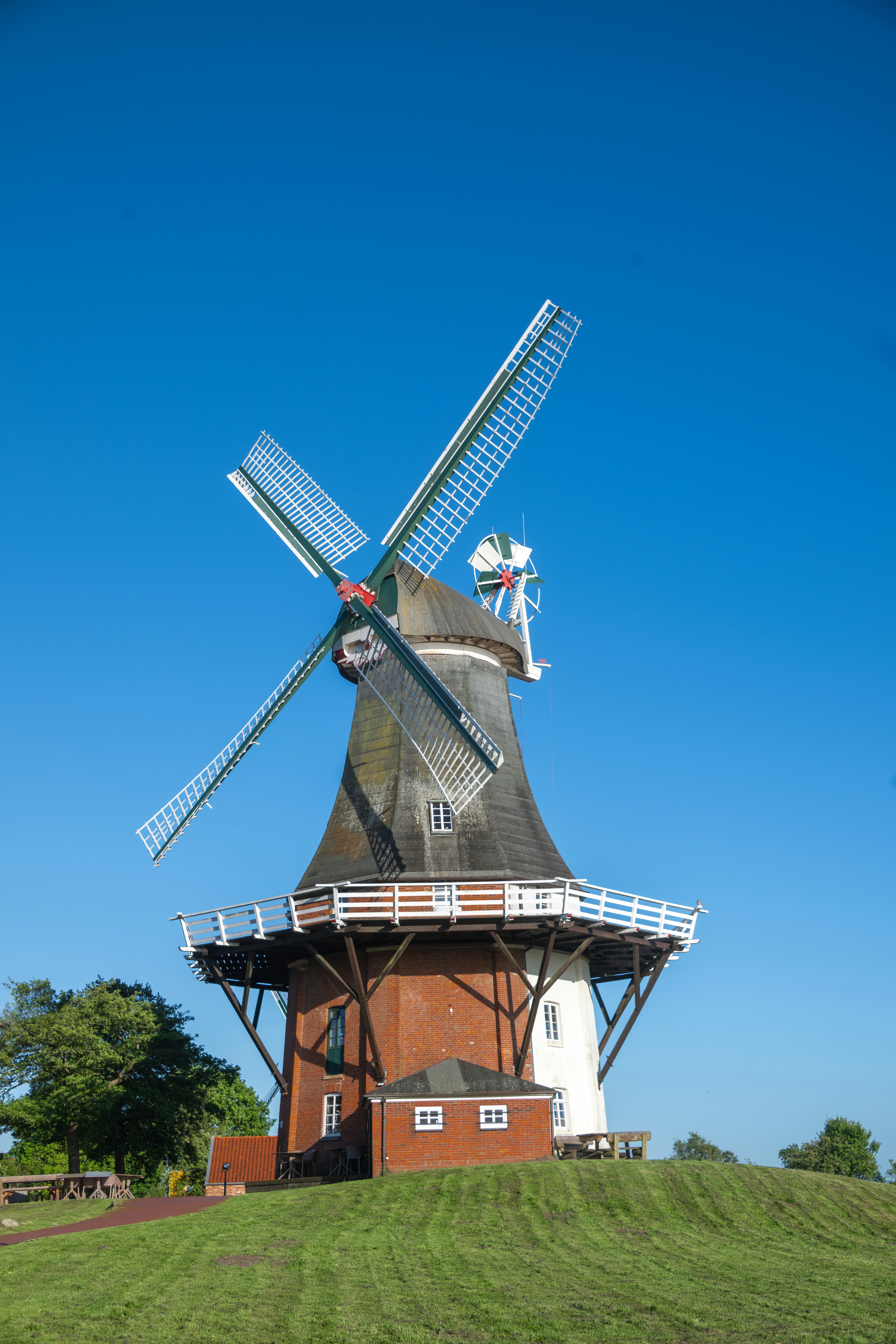 Traditional windmill on a grassy hill under blue sky.