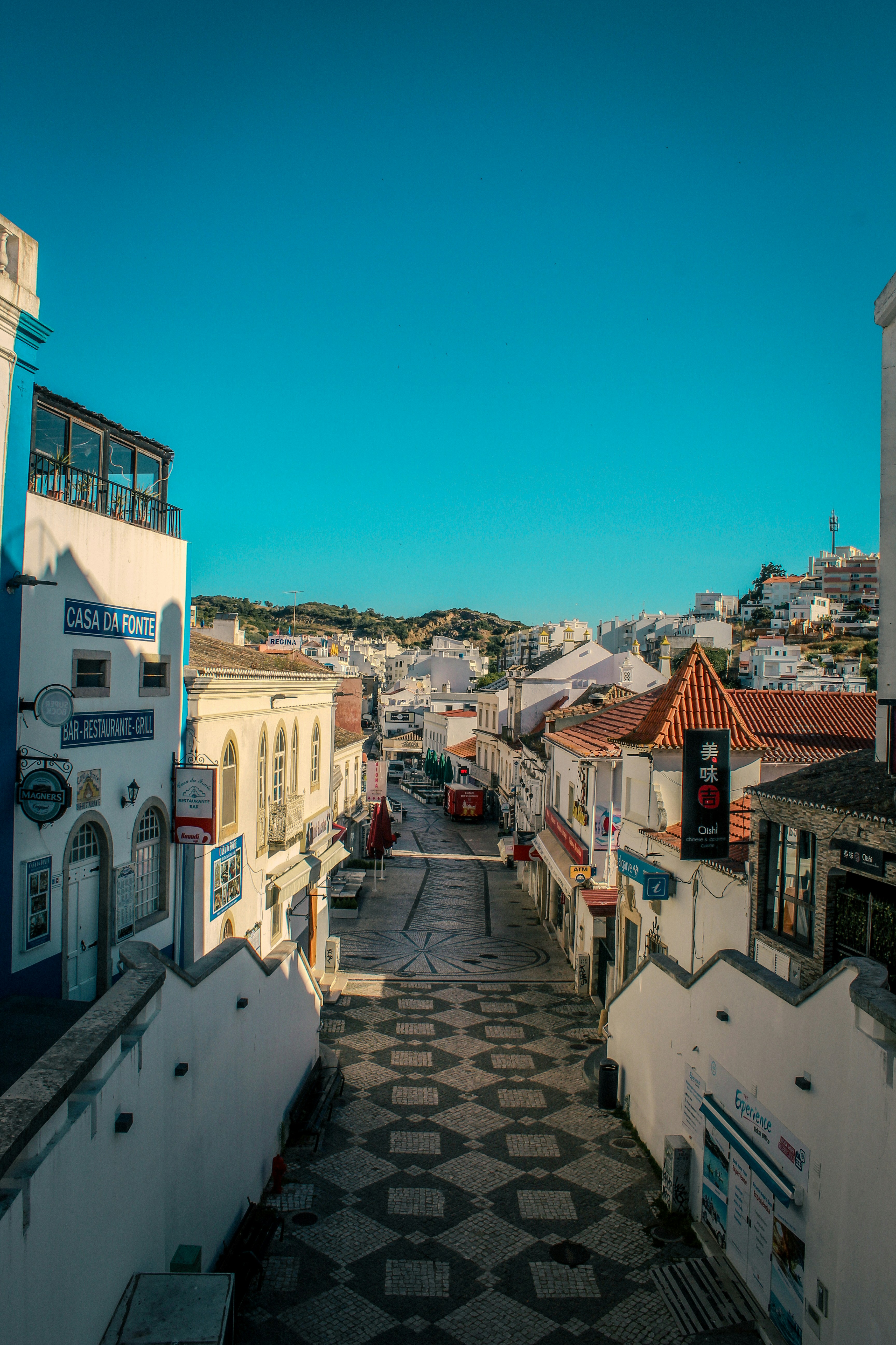 Slope of old town: a sunlit shopping street descending toward the bay
