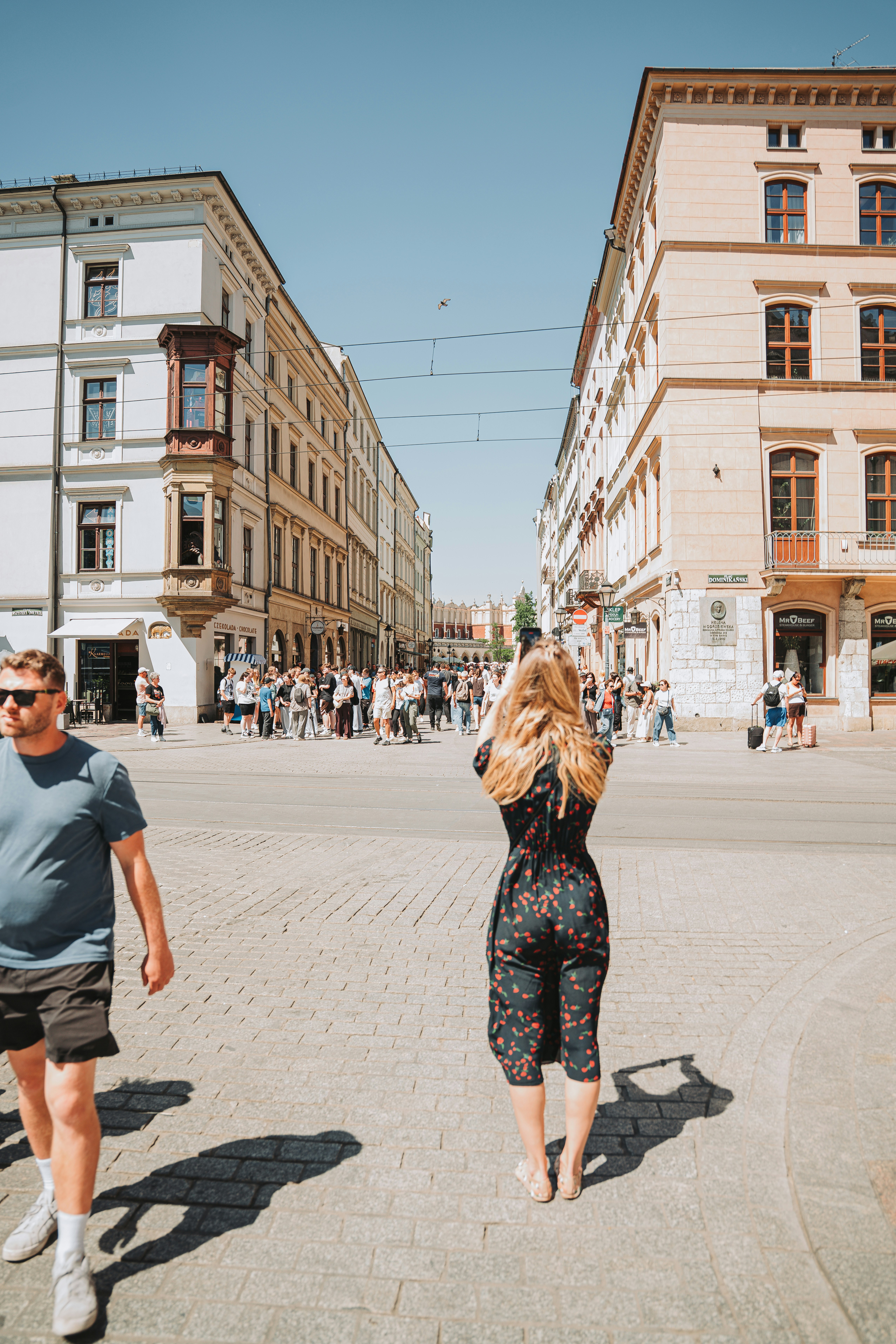 City Square Stroll: A Woman in Patterned Jumpsuit as Street Scene Unfolds