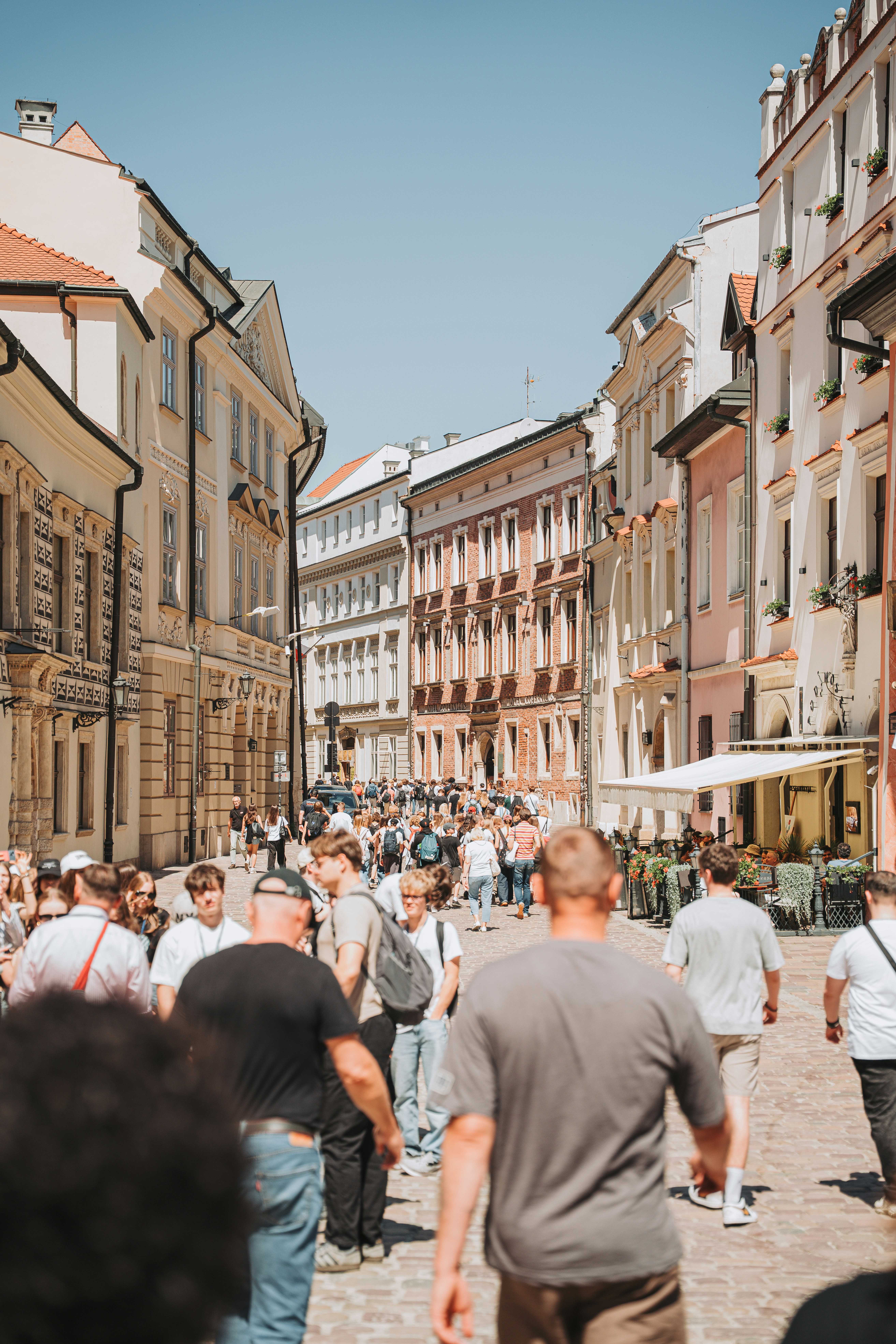 People walking on a sunny european street with historic buildings.