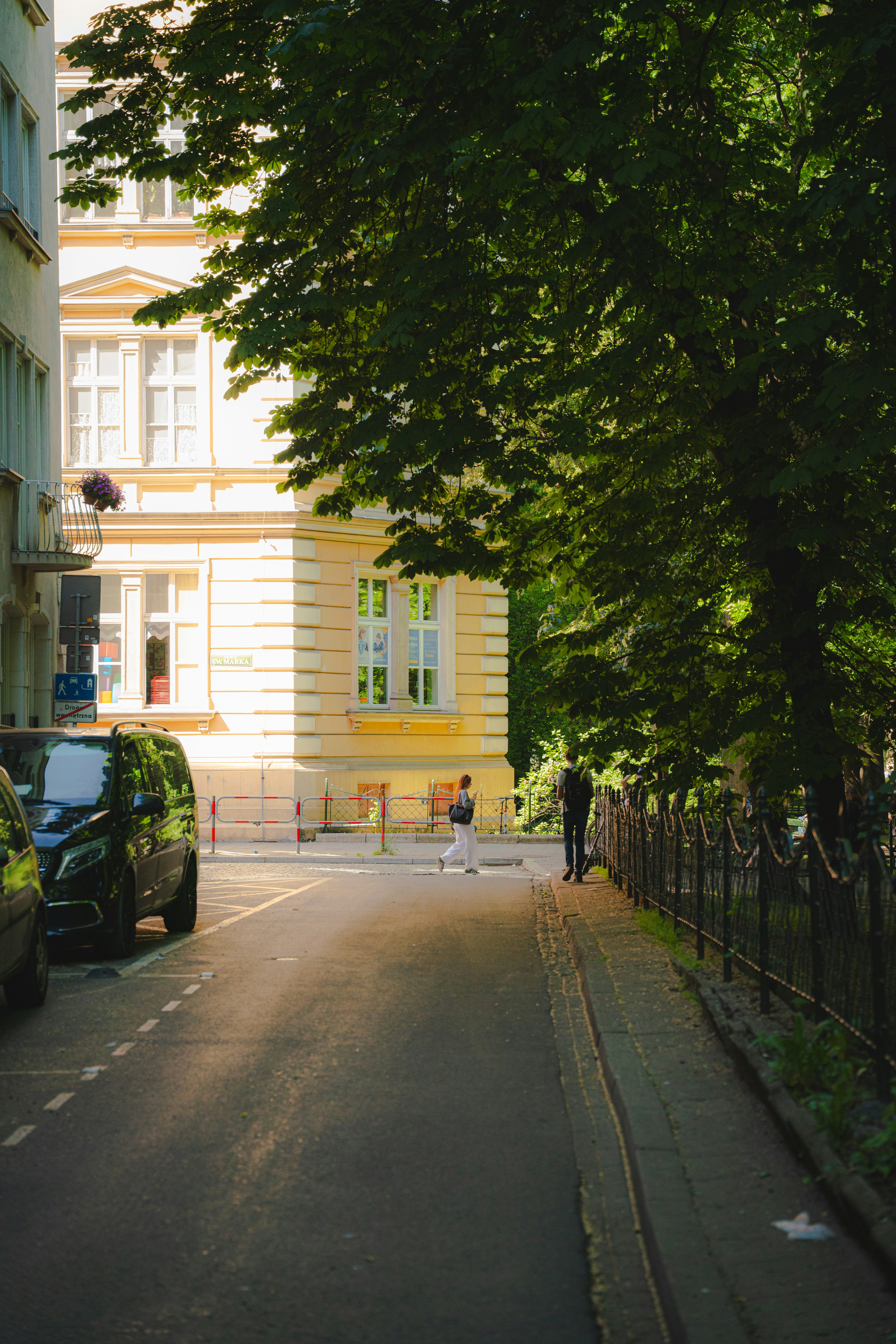 Sunlit Street Corridor Framed by Canary Facade and Canopy