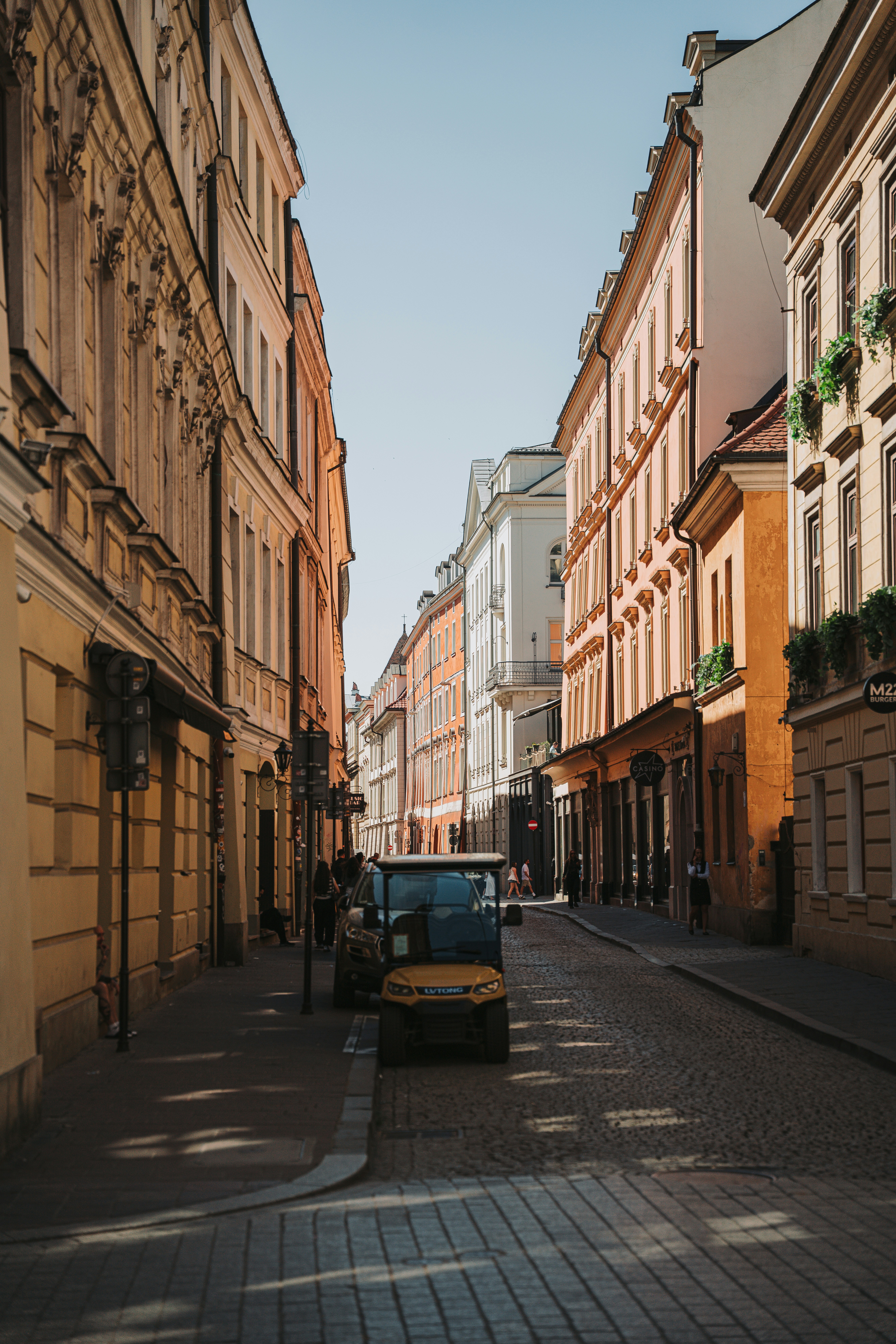 Cobbled Street Corridor: Sunlit Facades and a City Car