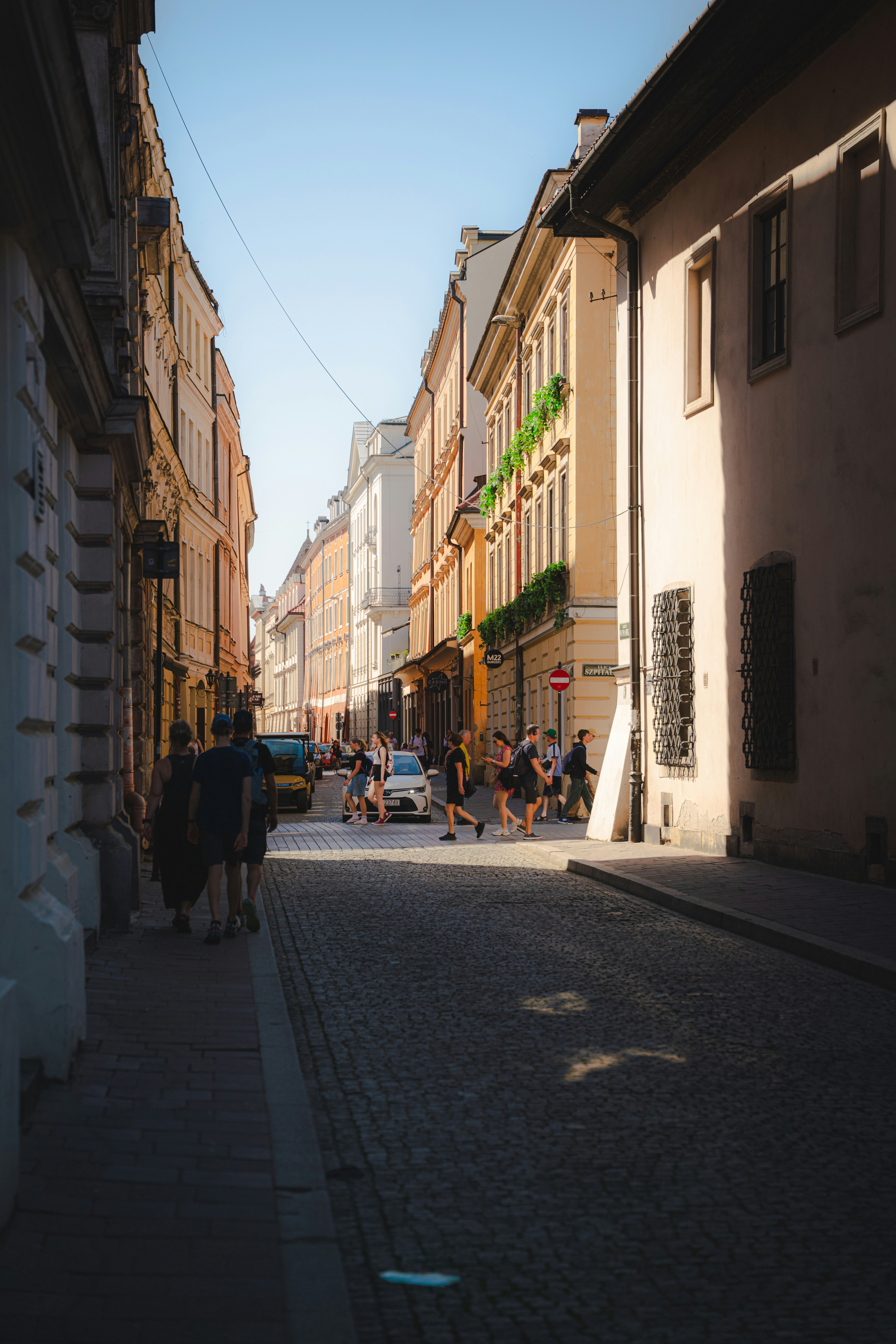 A narrow cobblestone street with old buildings and people walking.