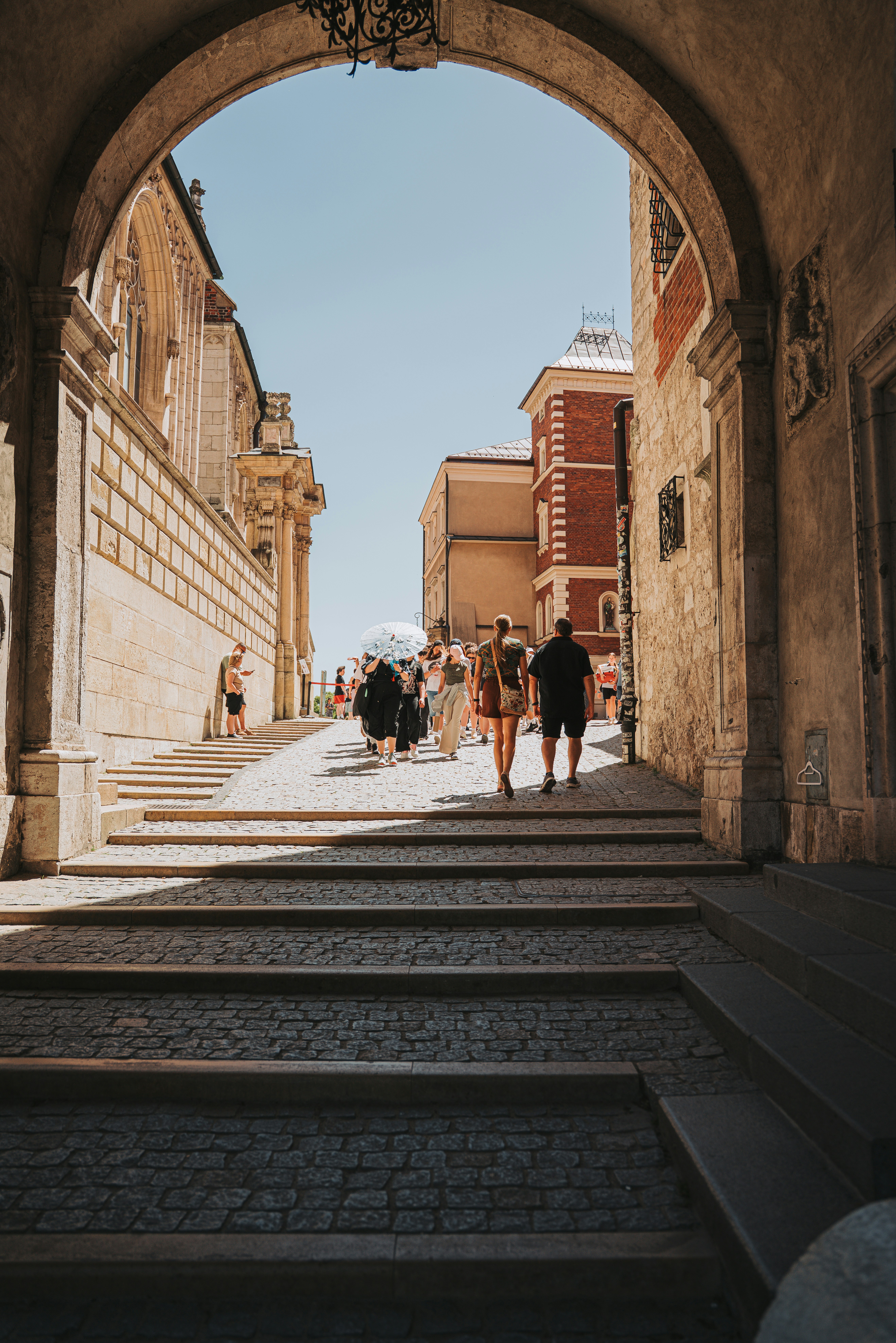 Sunlit Archway: A Narrow Stroll Through the Historic Square