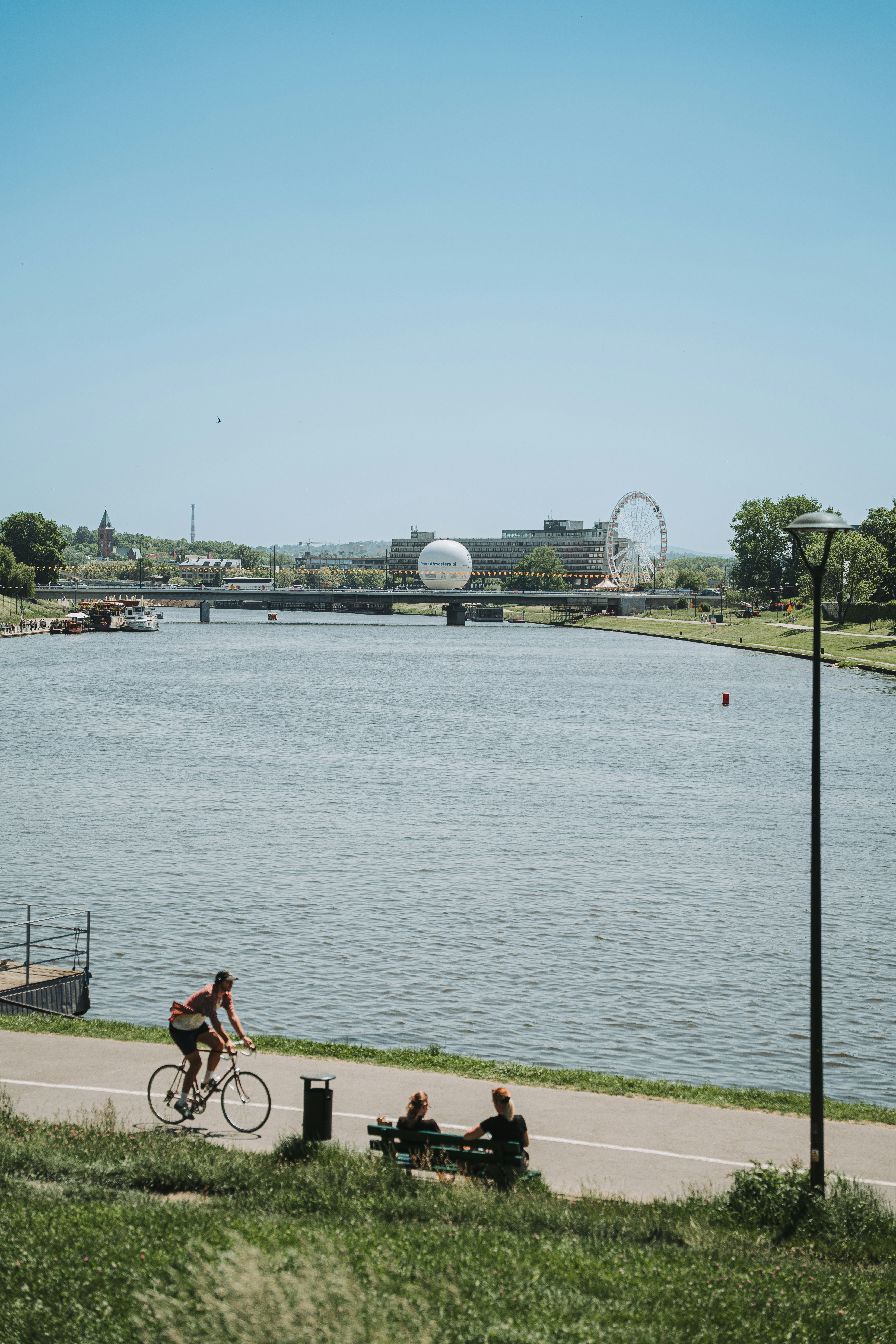 Riverside in Motion: Cyclist and Friends Beneath the Skyline