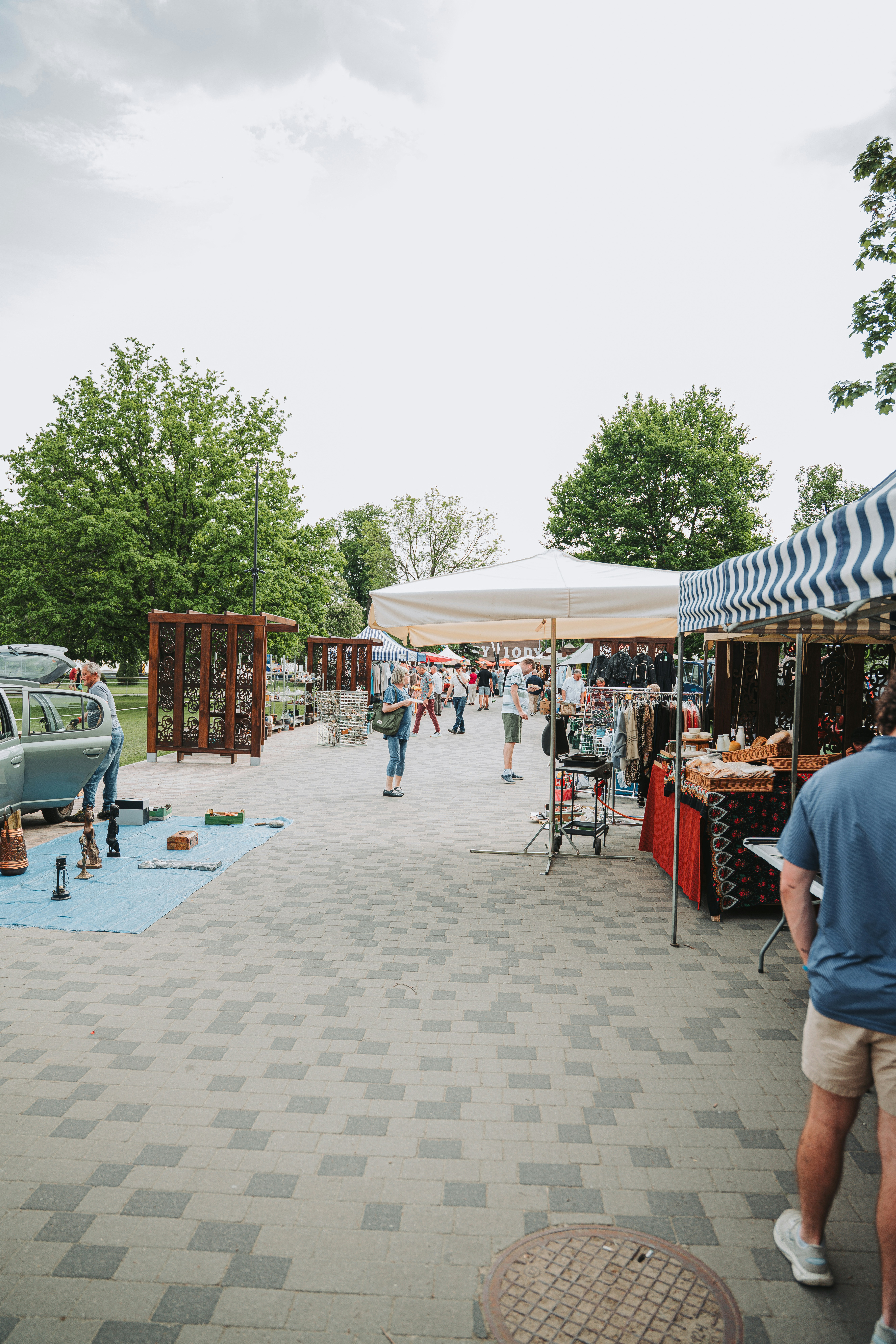 Market Day in the Shade: Wandering Shoppers Amid Stalls and Blue-Striped Canopies