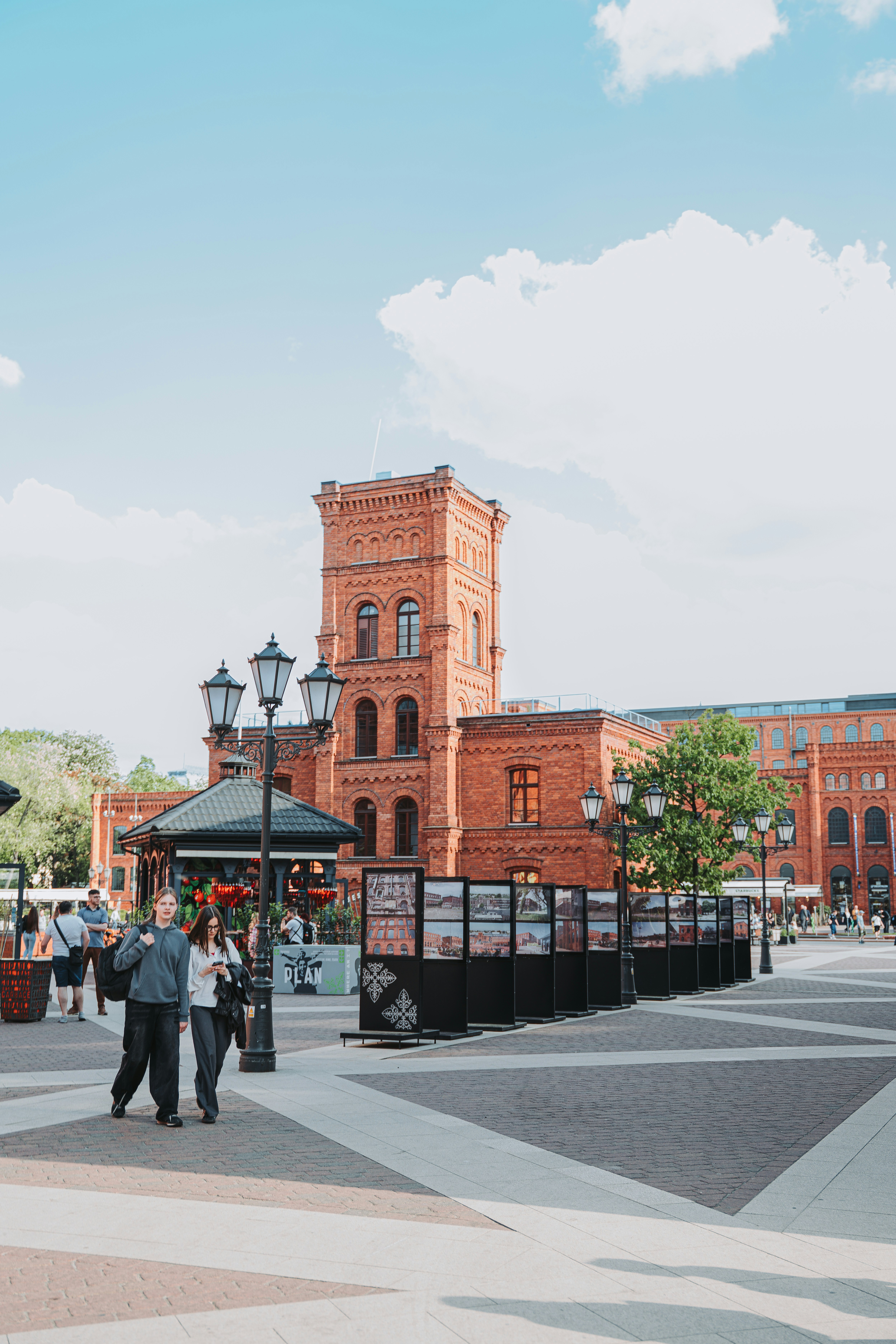 Brick Clocktower Plaza: People, Artifacts, and Arcades Under a Bright Sky