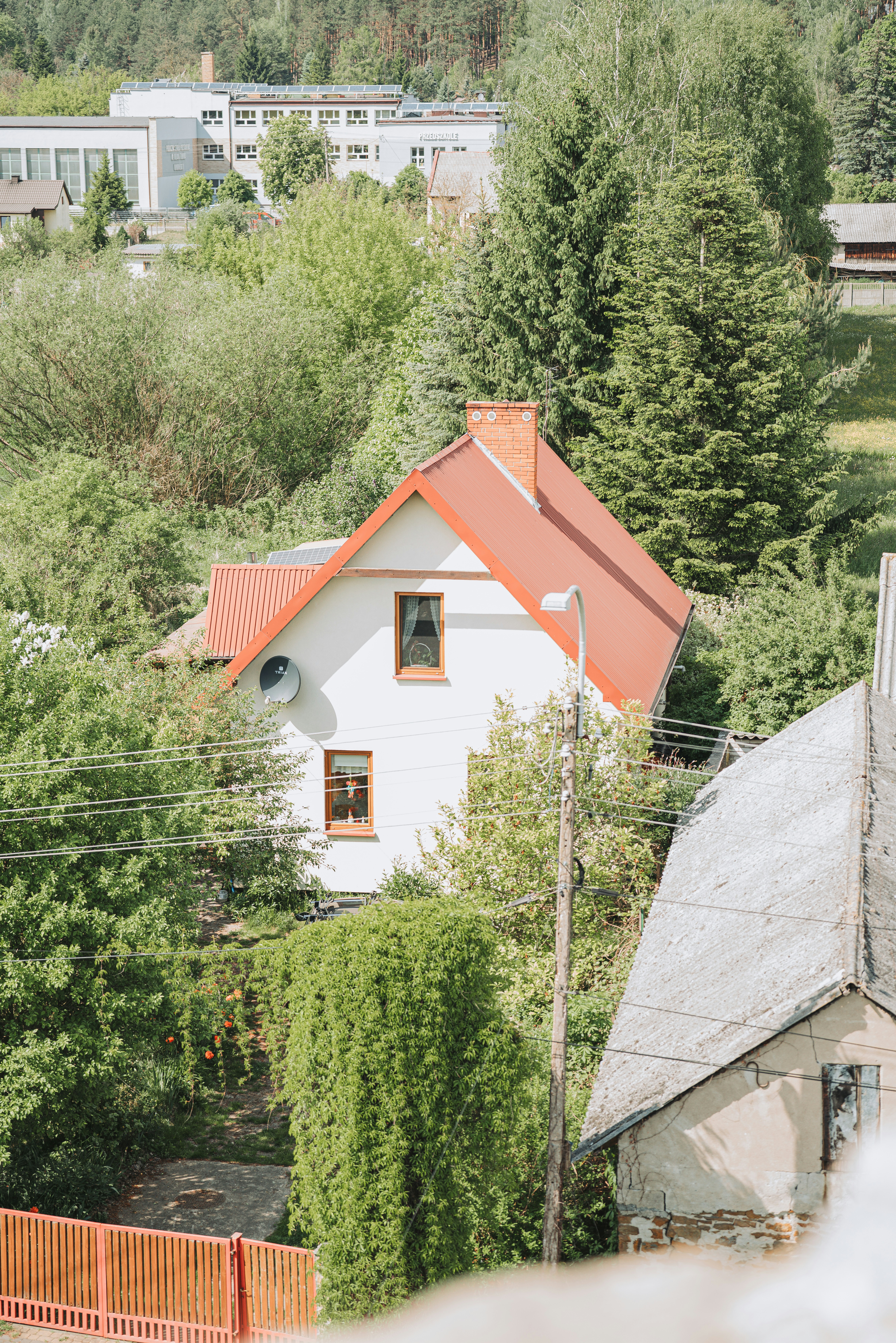 Orange-roofed cottage amid lush greenery tugging against a quiet village backdrop