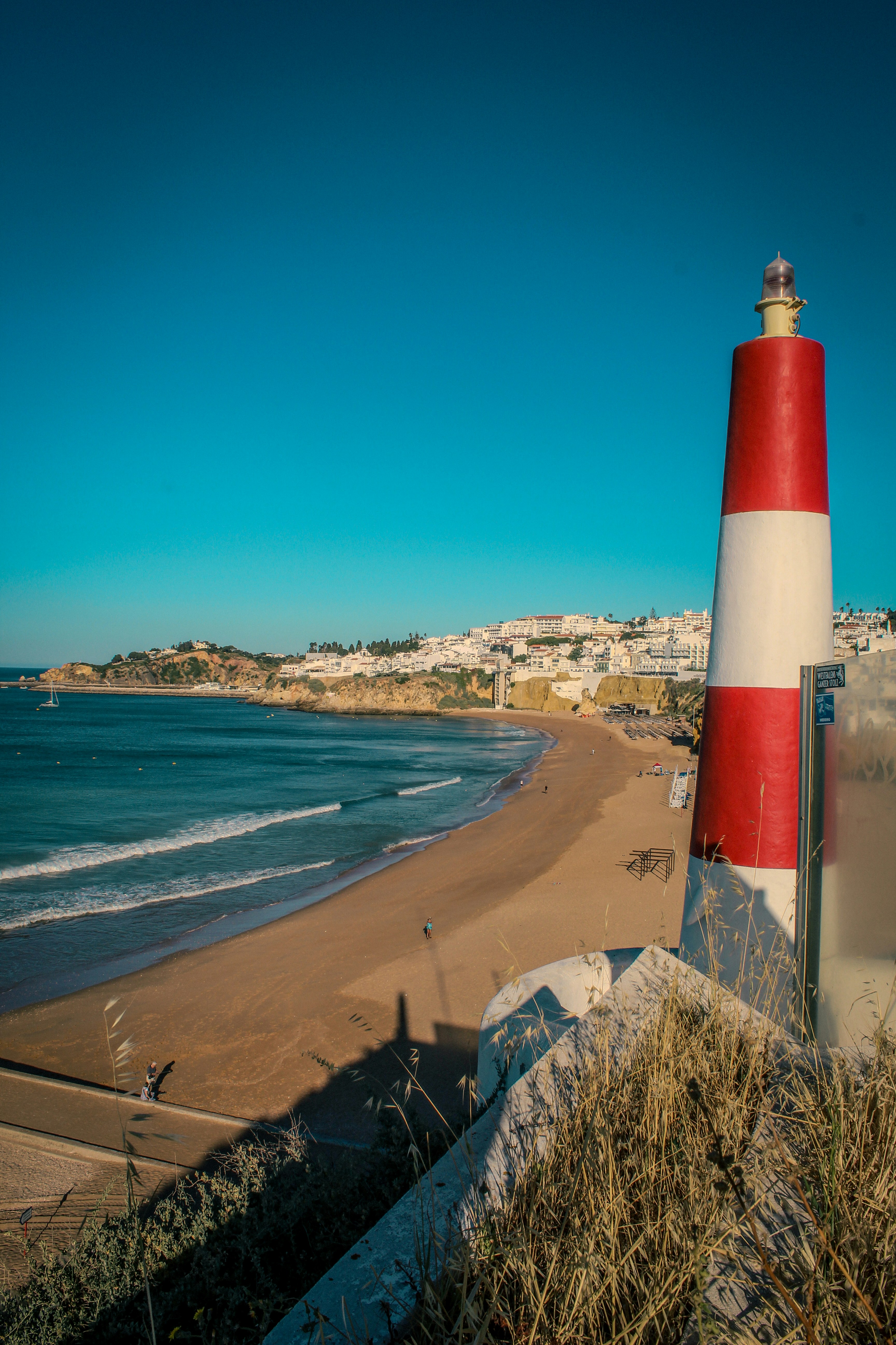 Red and white beacon over a sunlit seaside town