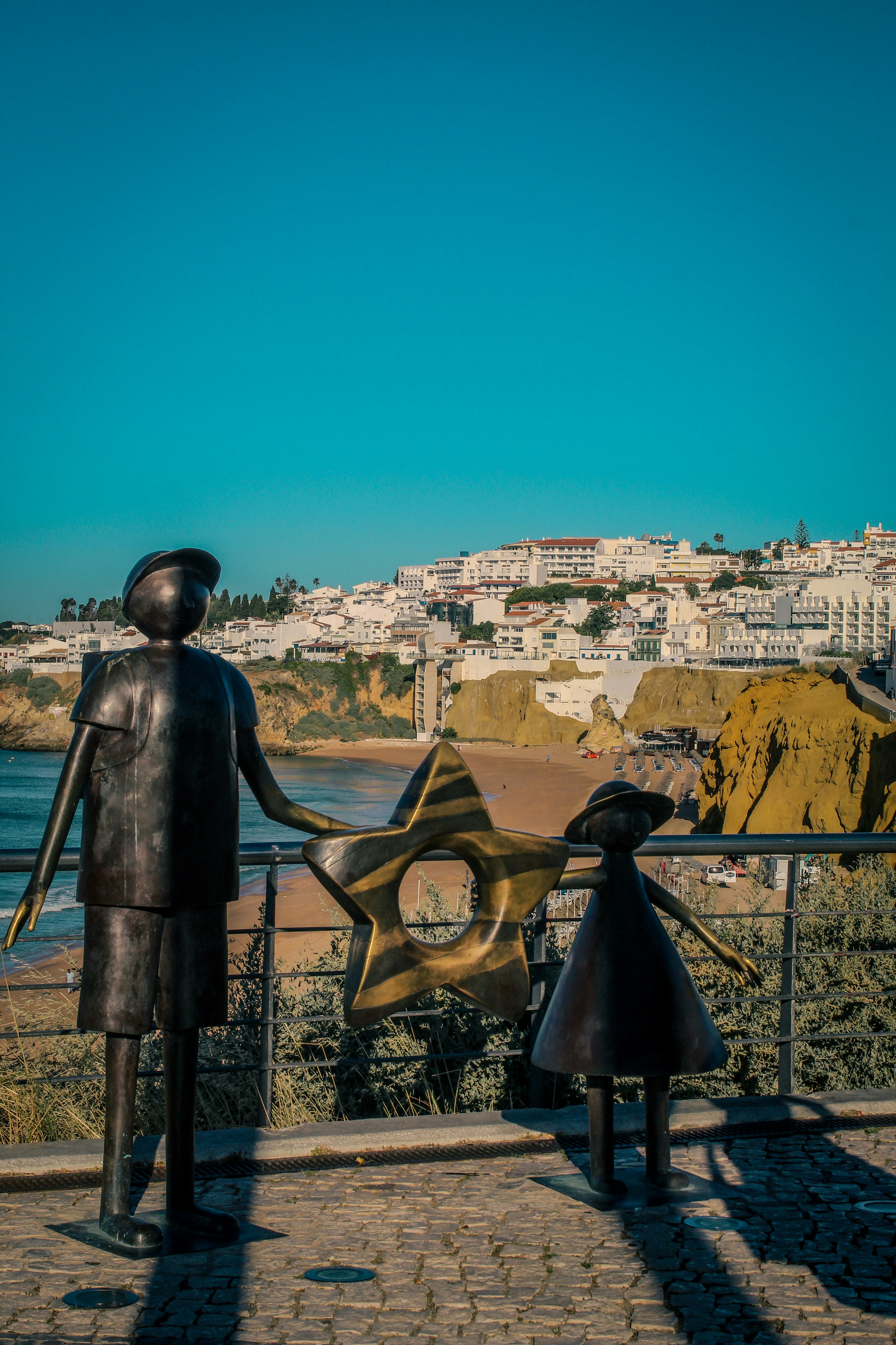 Star of the Sea: Bronze Figures Gazing Toward a Sunlit Cliff Town