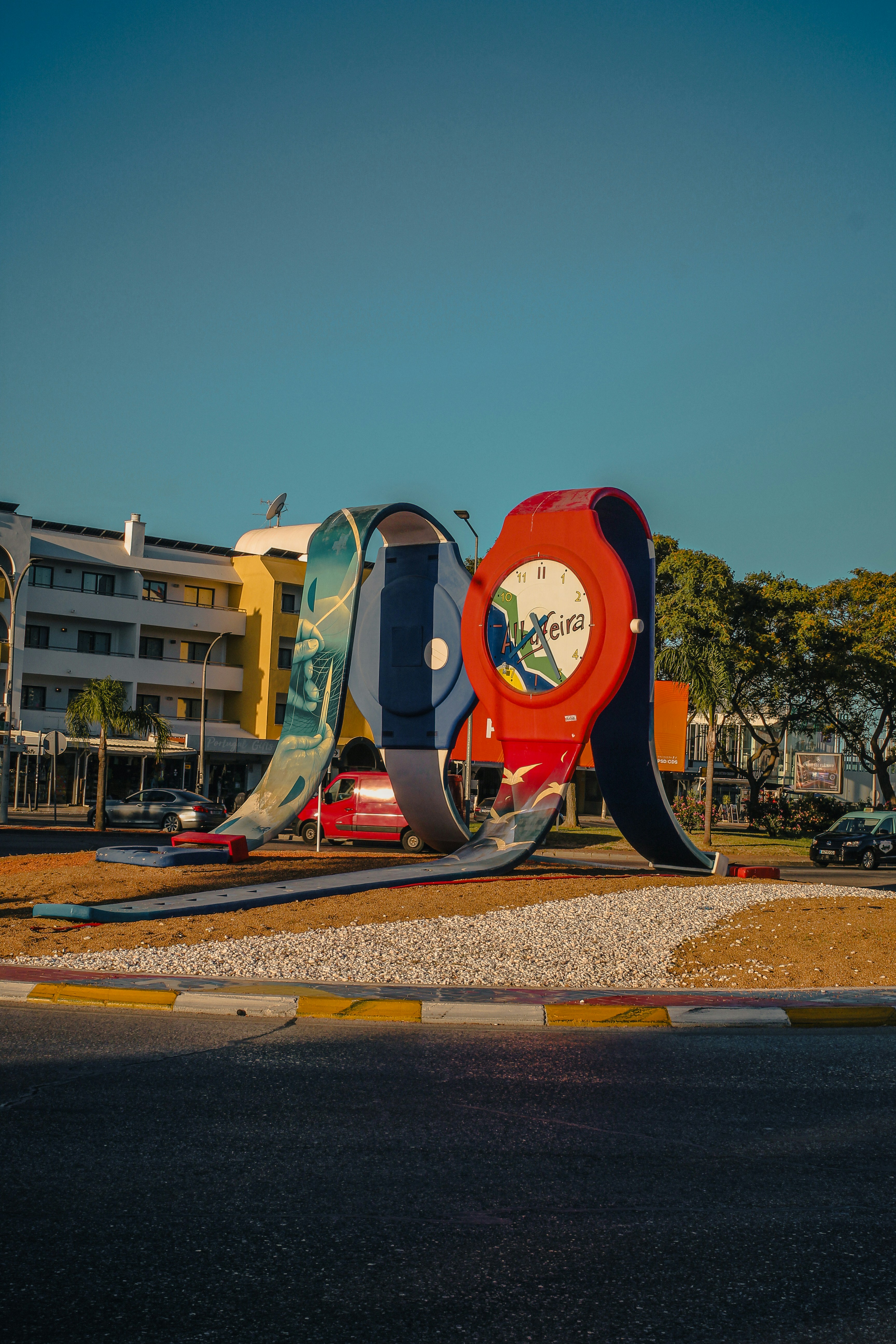 Playful clock-slide sculpture under a clear afternoon sky