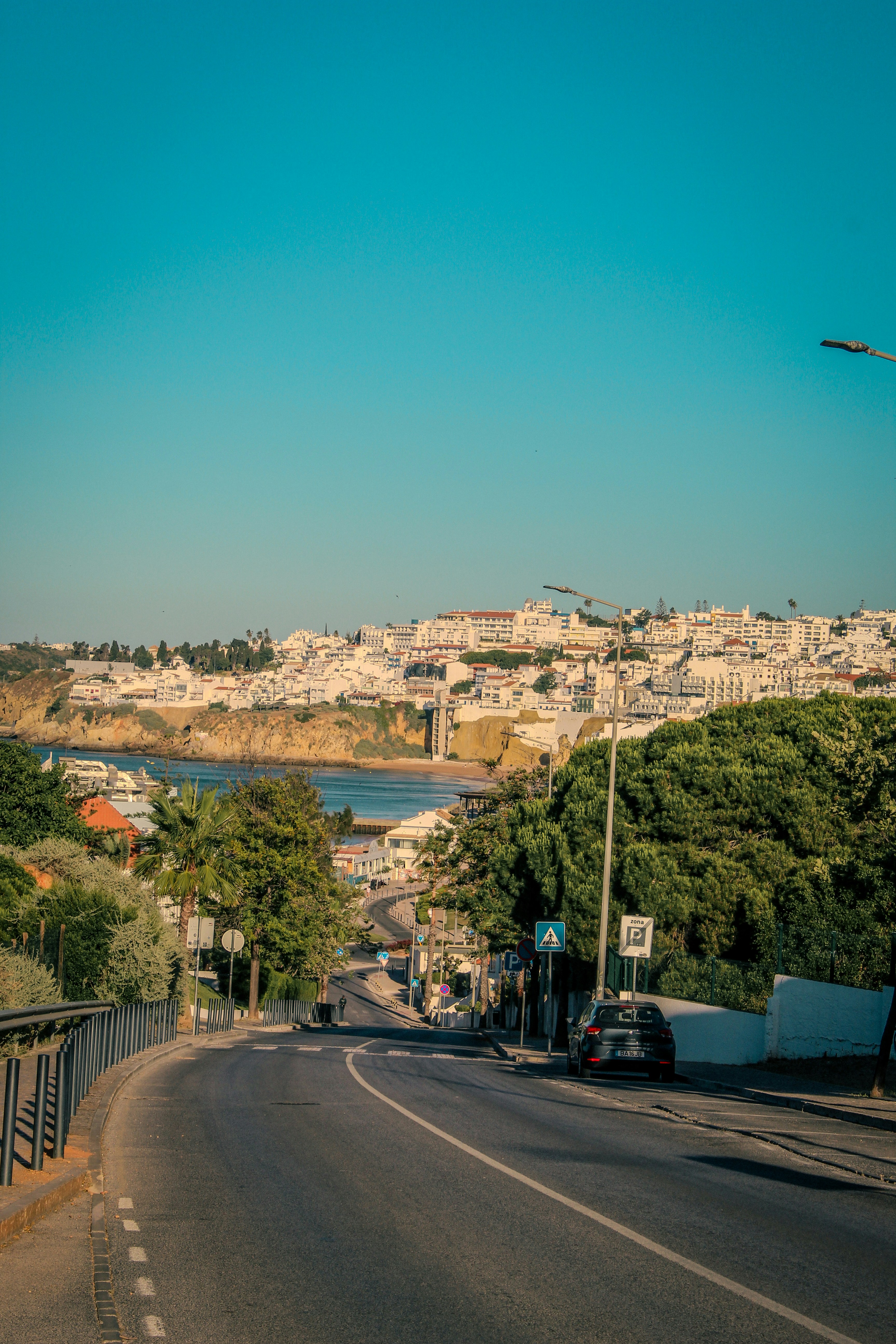 Coastal descent: a sunlit street toward a hillside town
