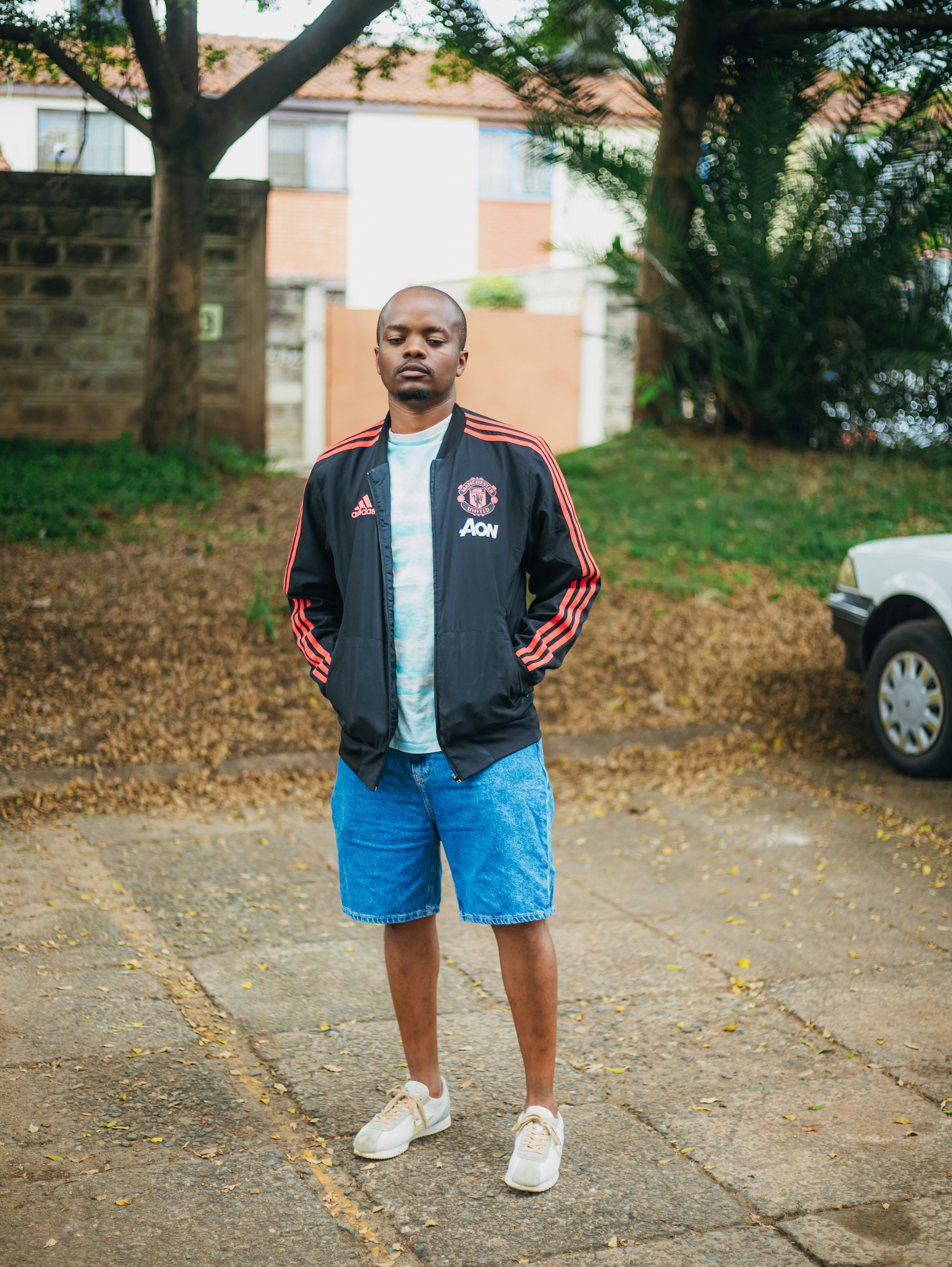 Centered in Urban Quiet: A Man in a Manchester Jacket Stands Squarely in a Parking Lot