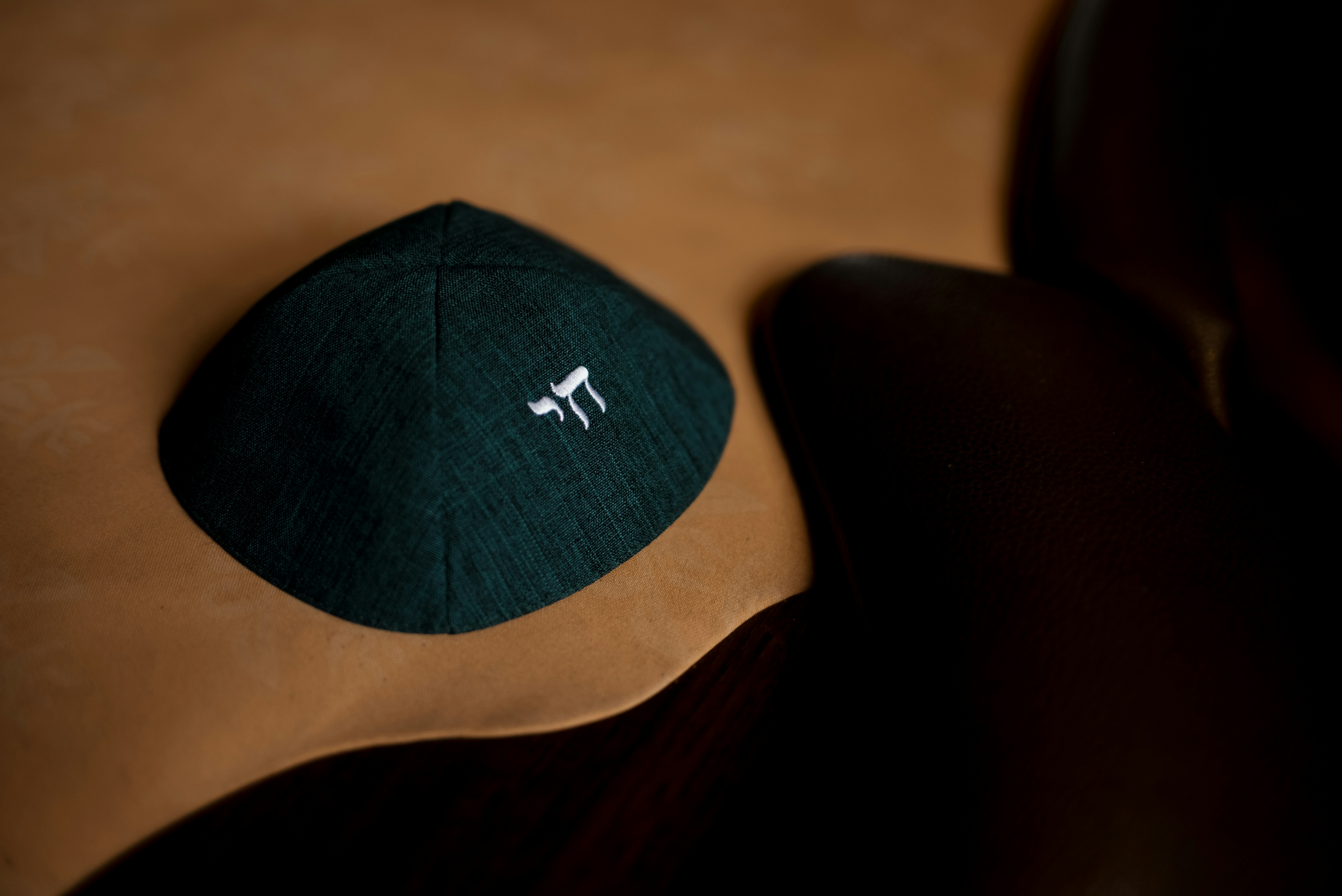 A Quiet Circle: The Dark Cap with White Stitch on Tan Sands