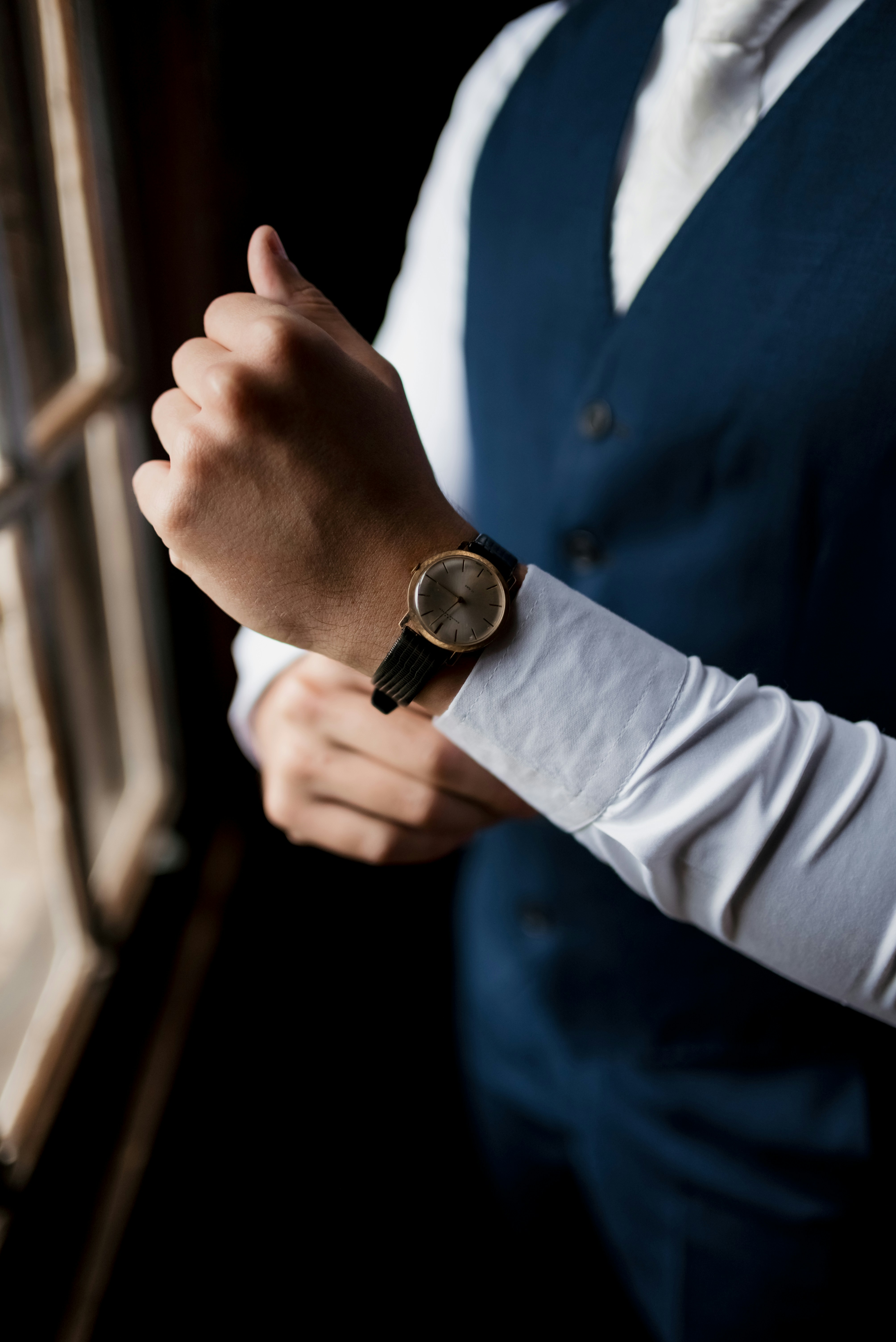Man in a blue vest adjusting his wrist watch.