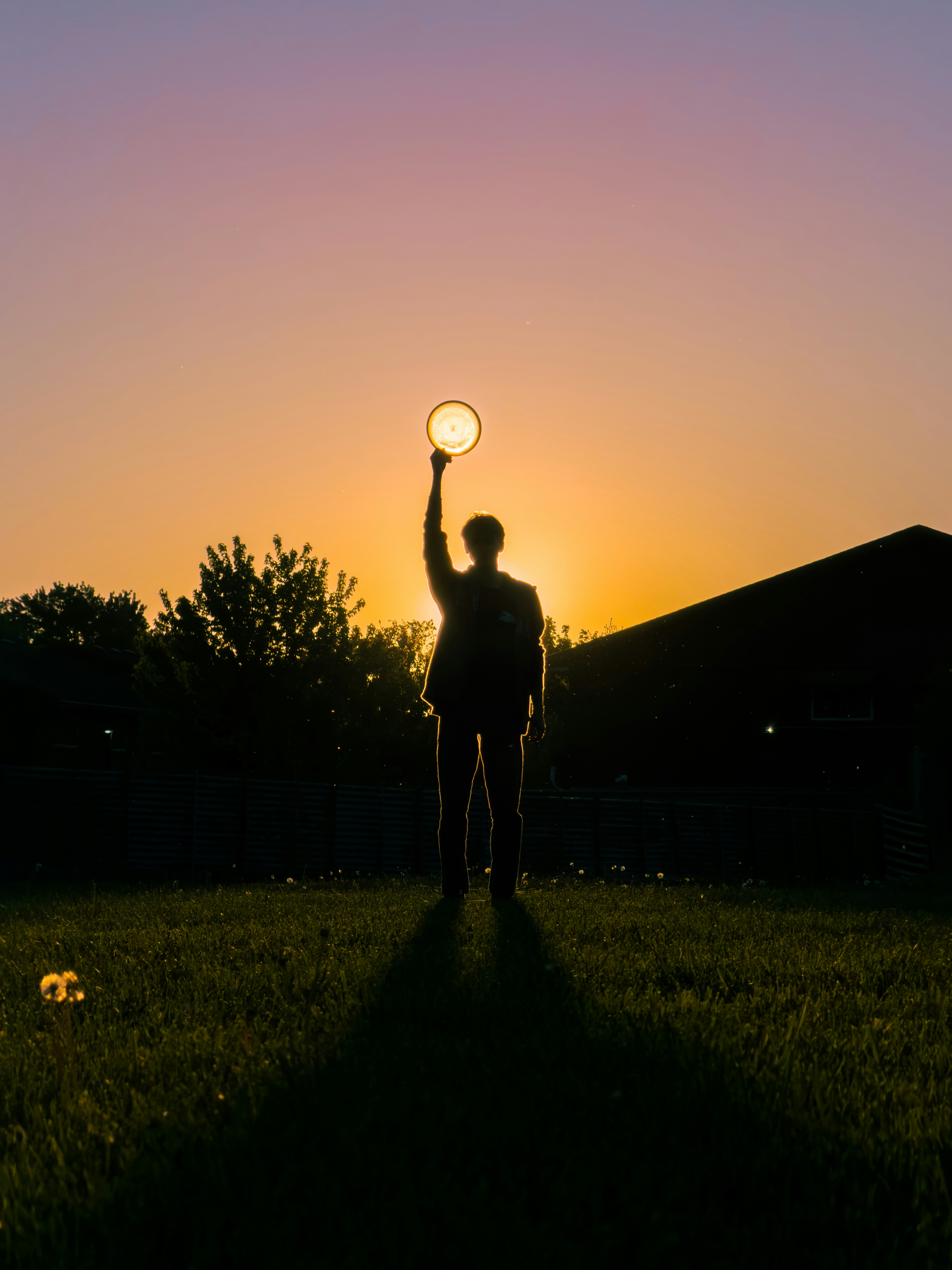 Silhouette Under a Rising Sun: A Child of the Evening Field Lifts a Lantern
