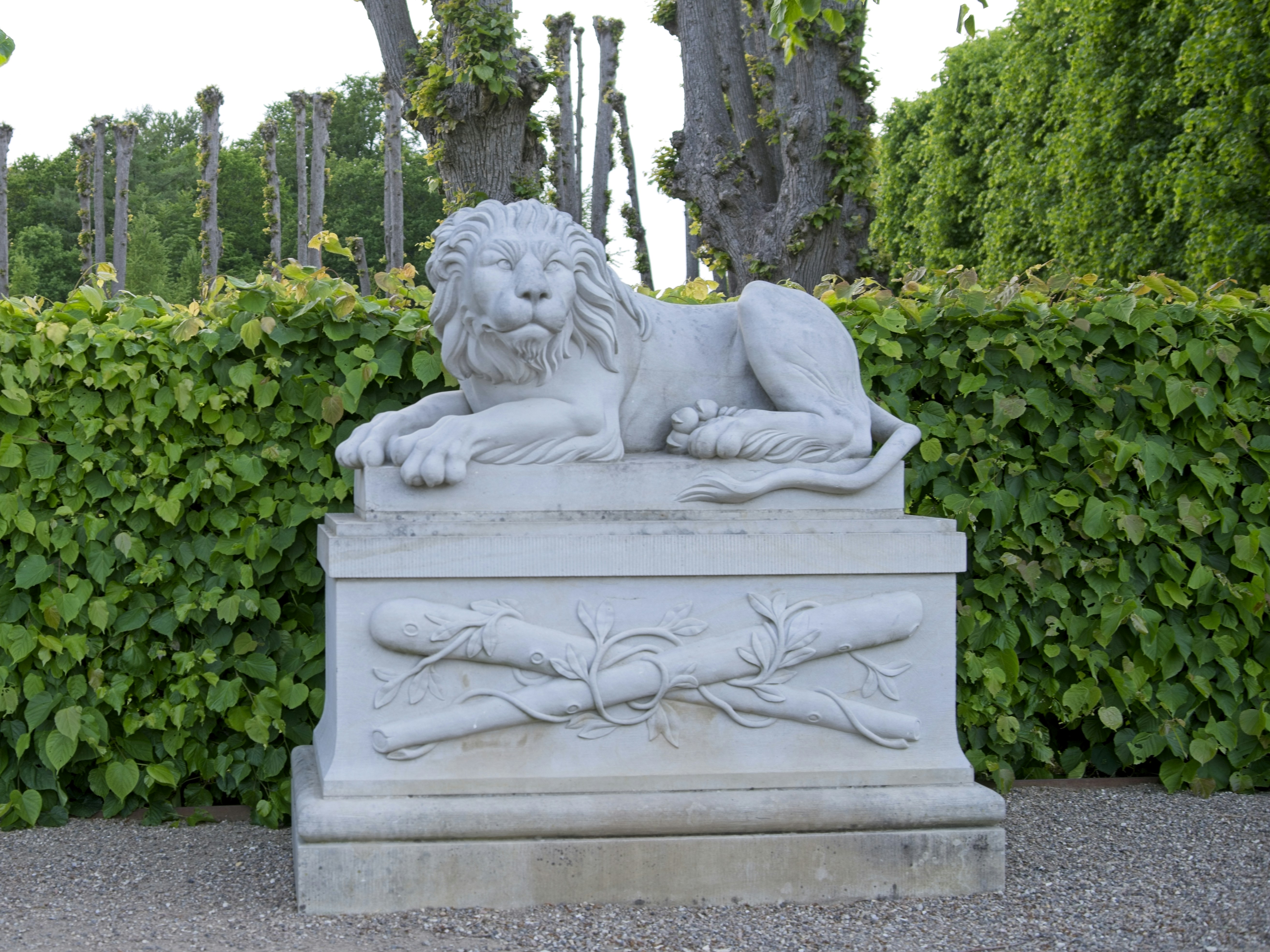 Stone Guardian: A Lying Lion on a Tiled Plinth Surrounded by Ivy