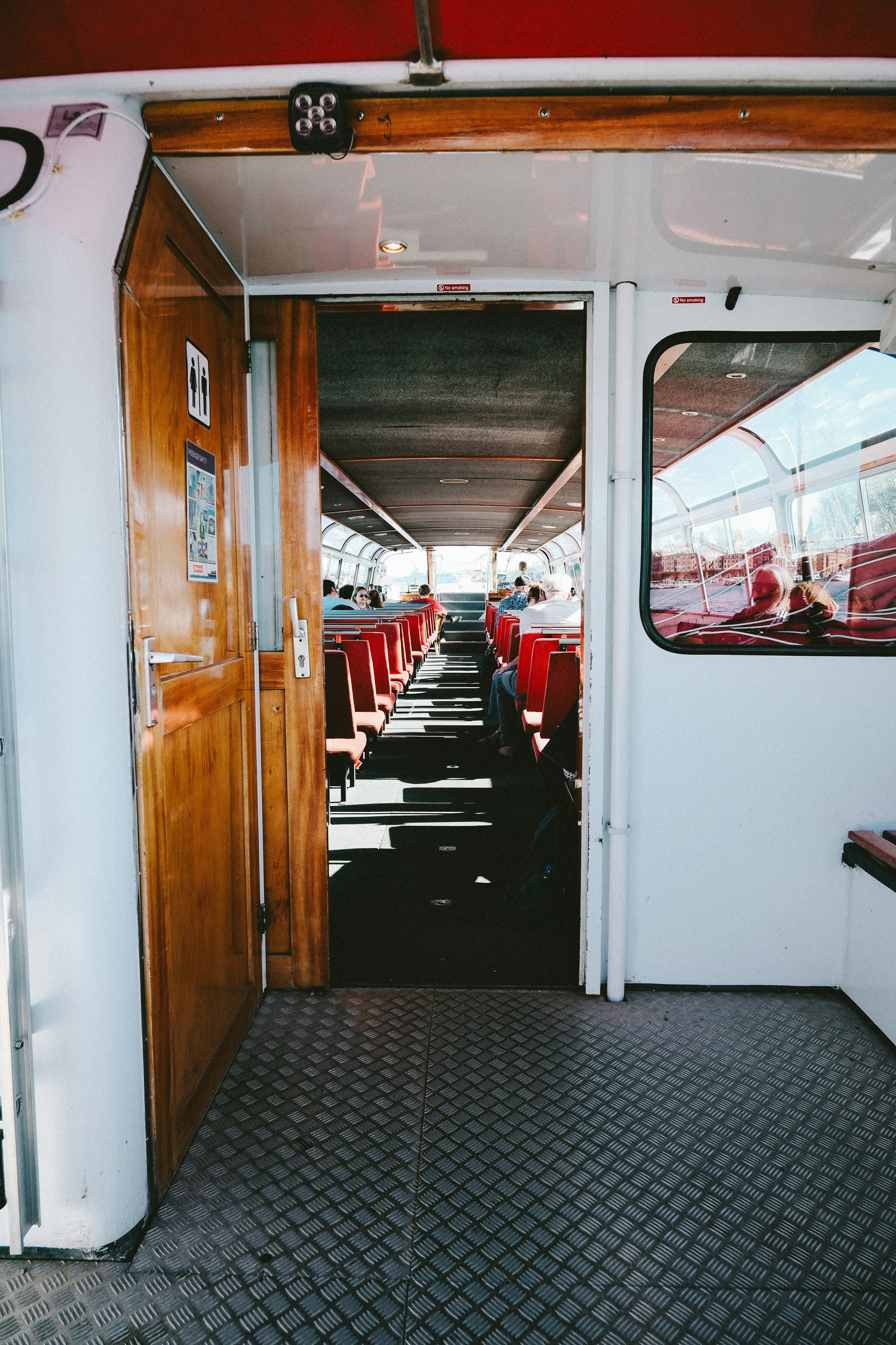 Doorway to a Quiet Carriage: Red Seats and Sunlit Corridor