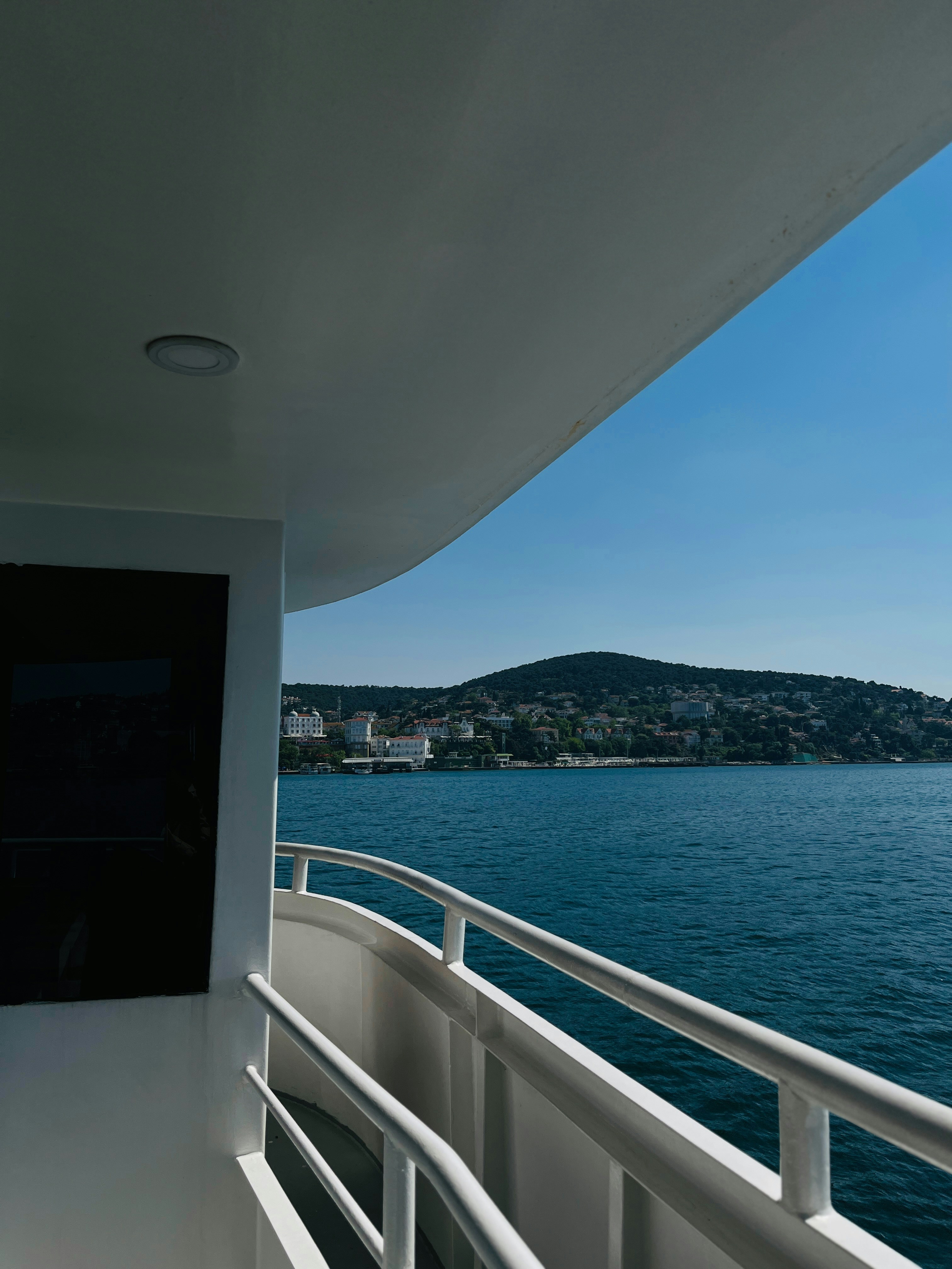 View from a boat over blue water towards distant land.