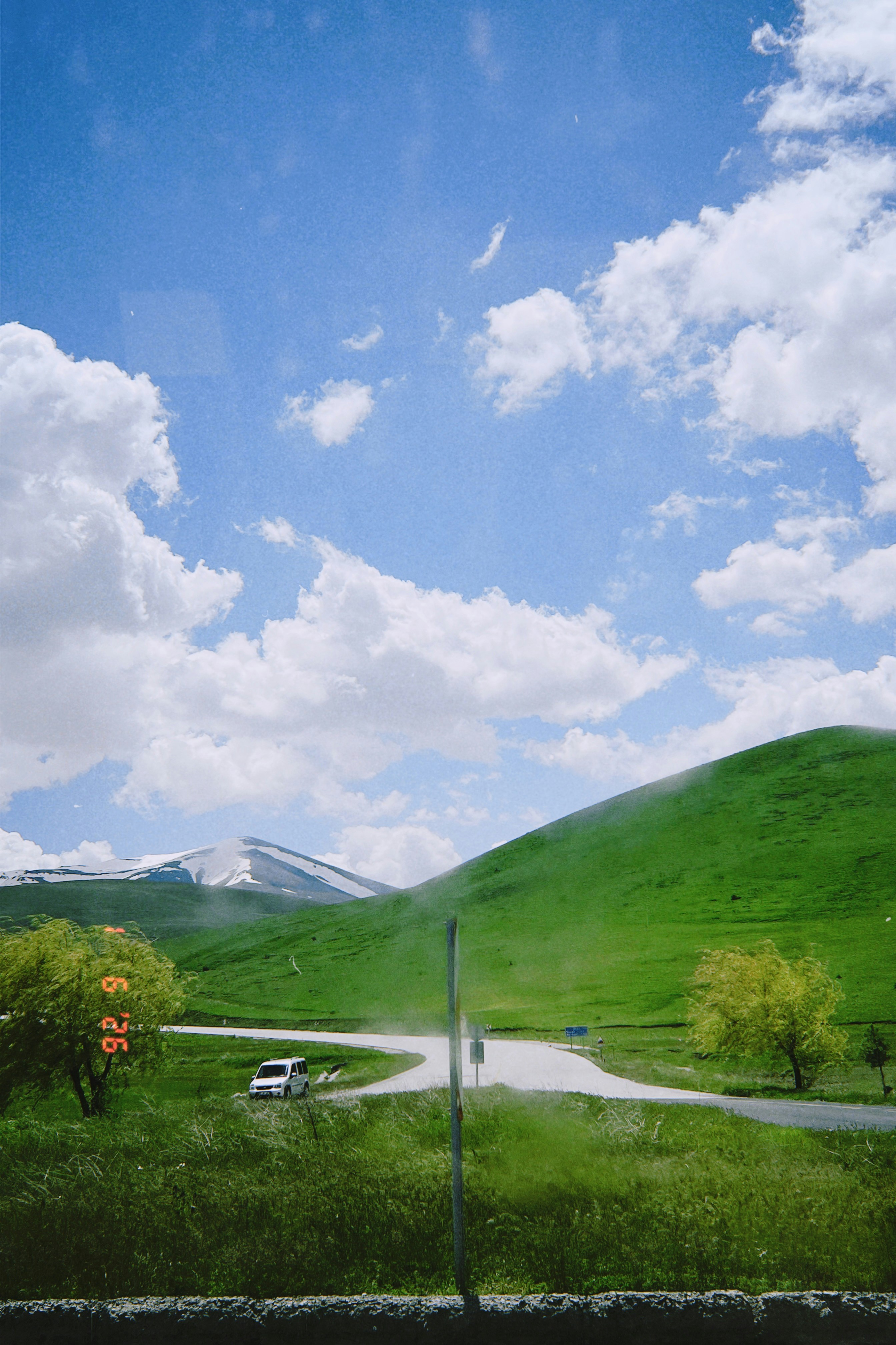 Scenic landscape with green hills, road, and distant snow mountains.