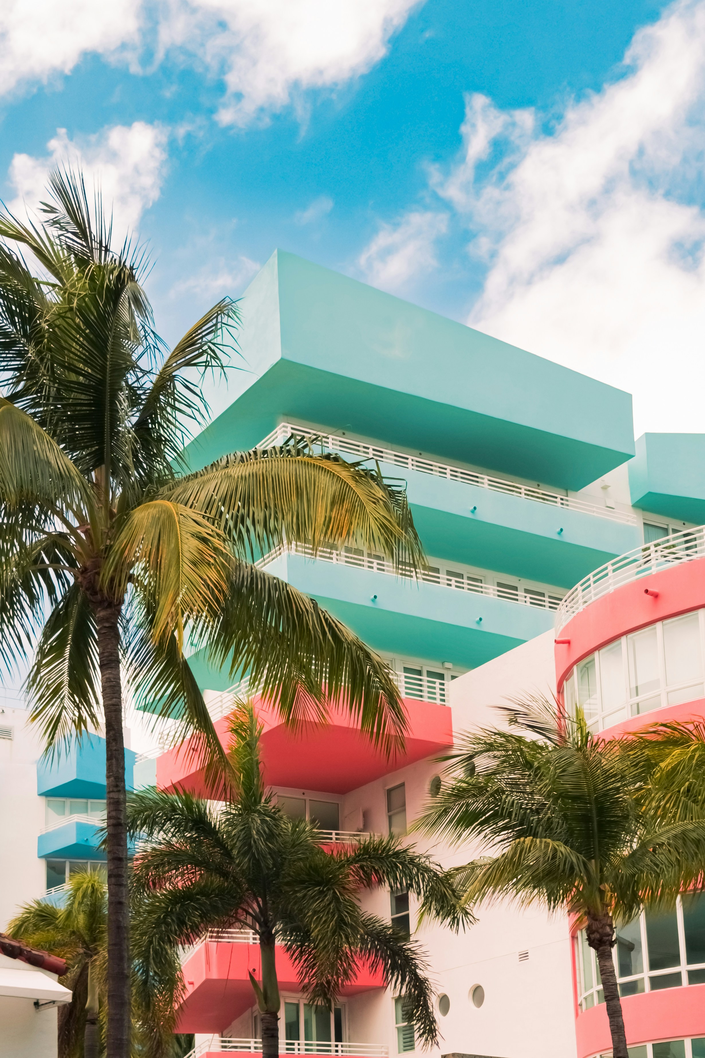 Pastel tropical architecture framed by palm trees under a bright summer sky