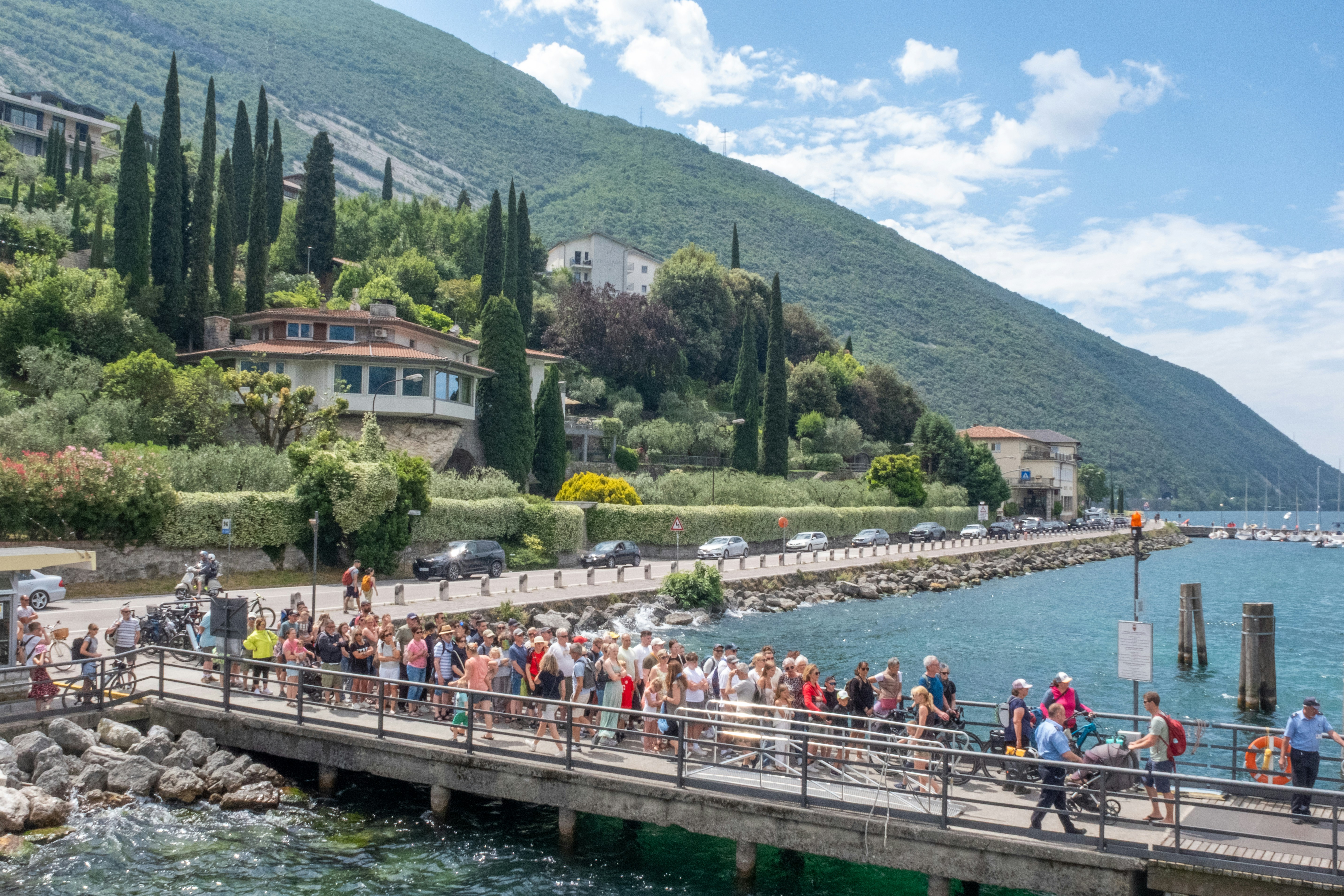 Crowded Lakeside Pier: People, Boats, and Summer Hillside Homes