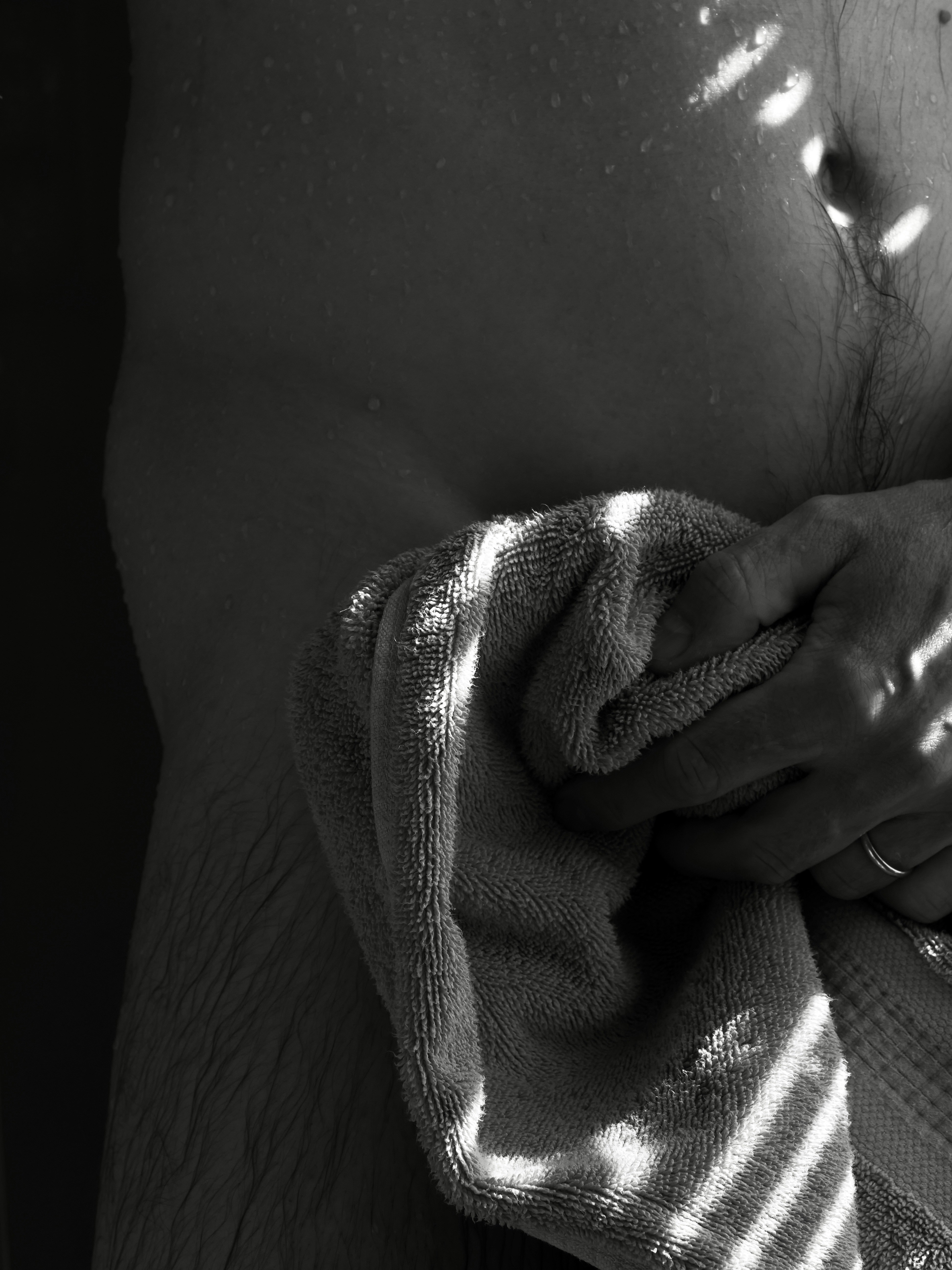 Muted Intimacy: A Hand Clutches a Towel Against the Shoulder in Soft Shadow