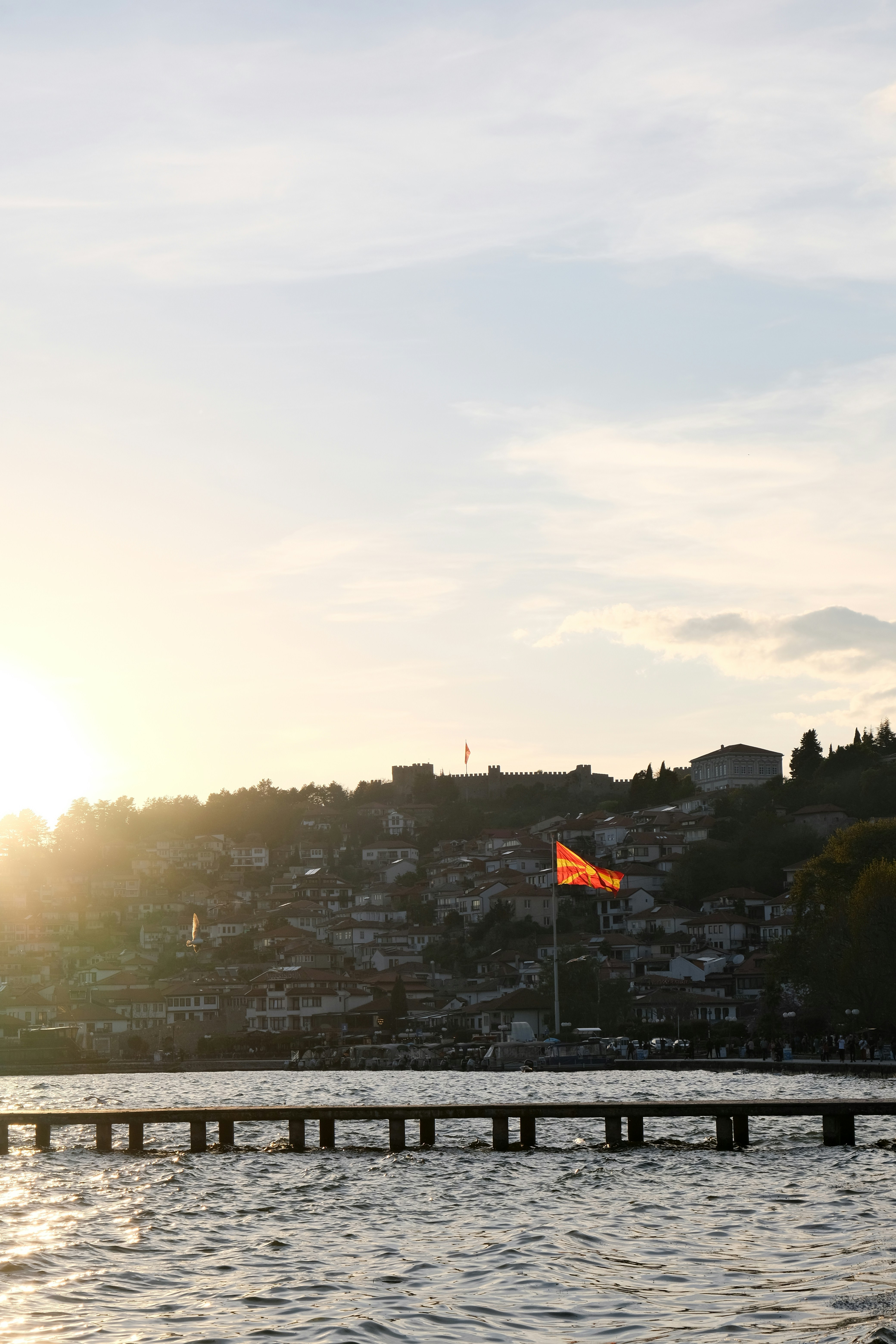 Golden Hour Over a Lakeside Town with a Red Flag