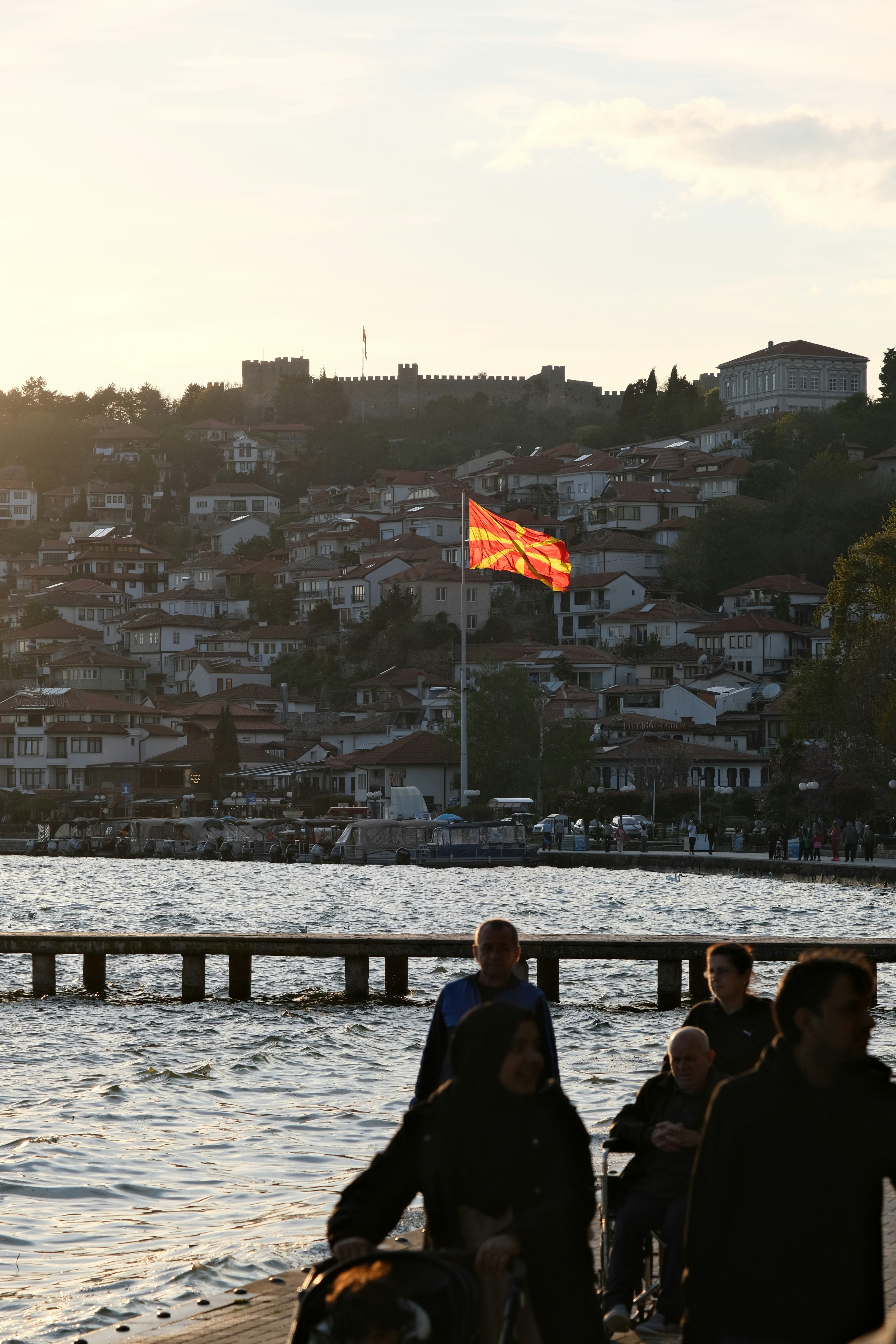 Flag over the hillside town as waves lap a quiet pier