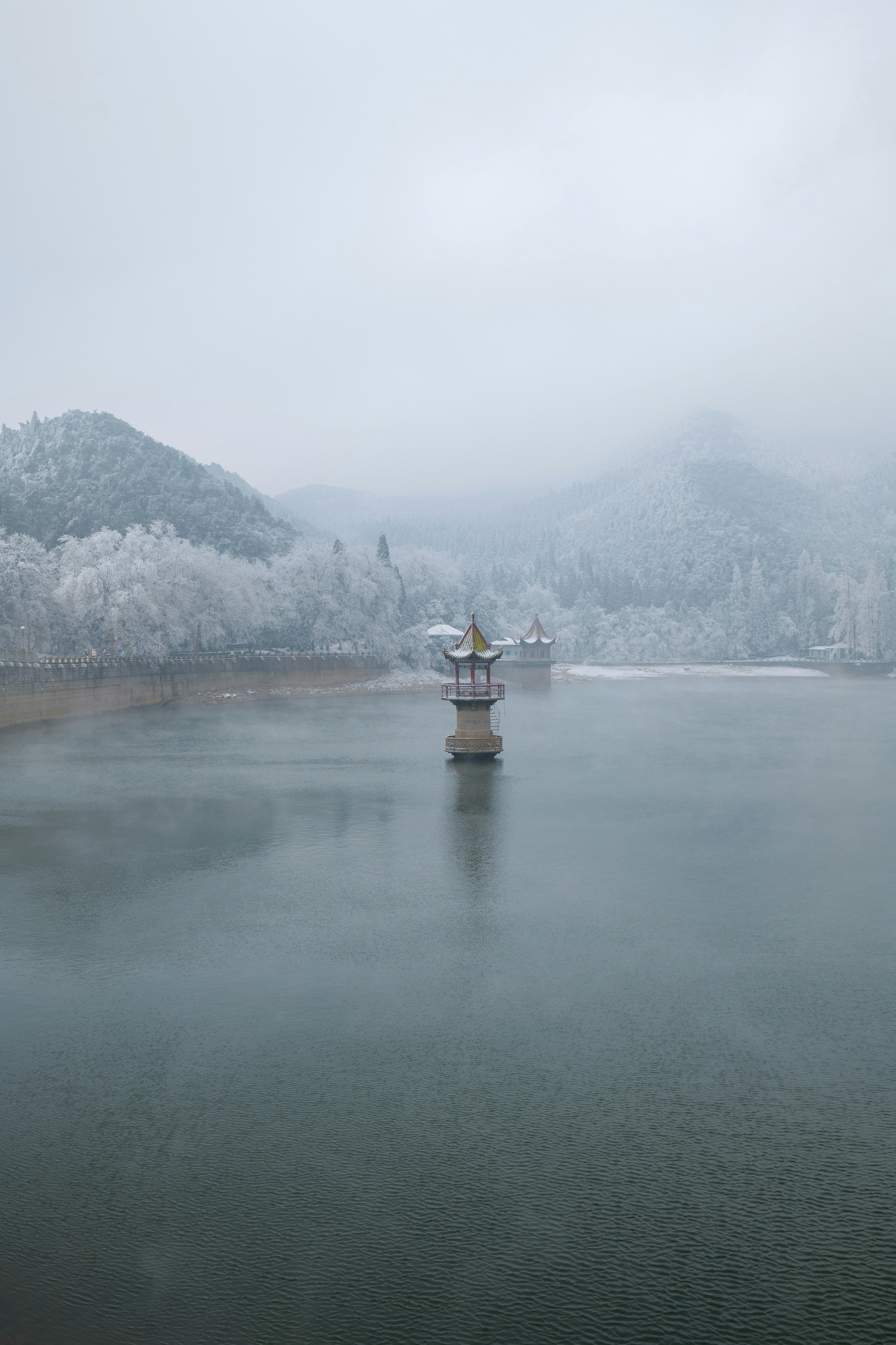 Pagoda on a tranquil misted lake surrounded by snow-dusted mountains