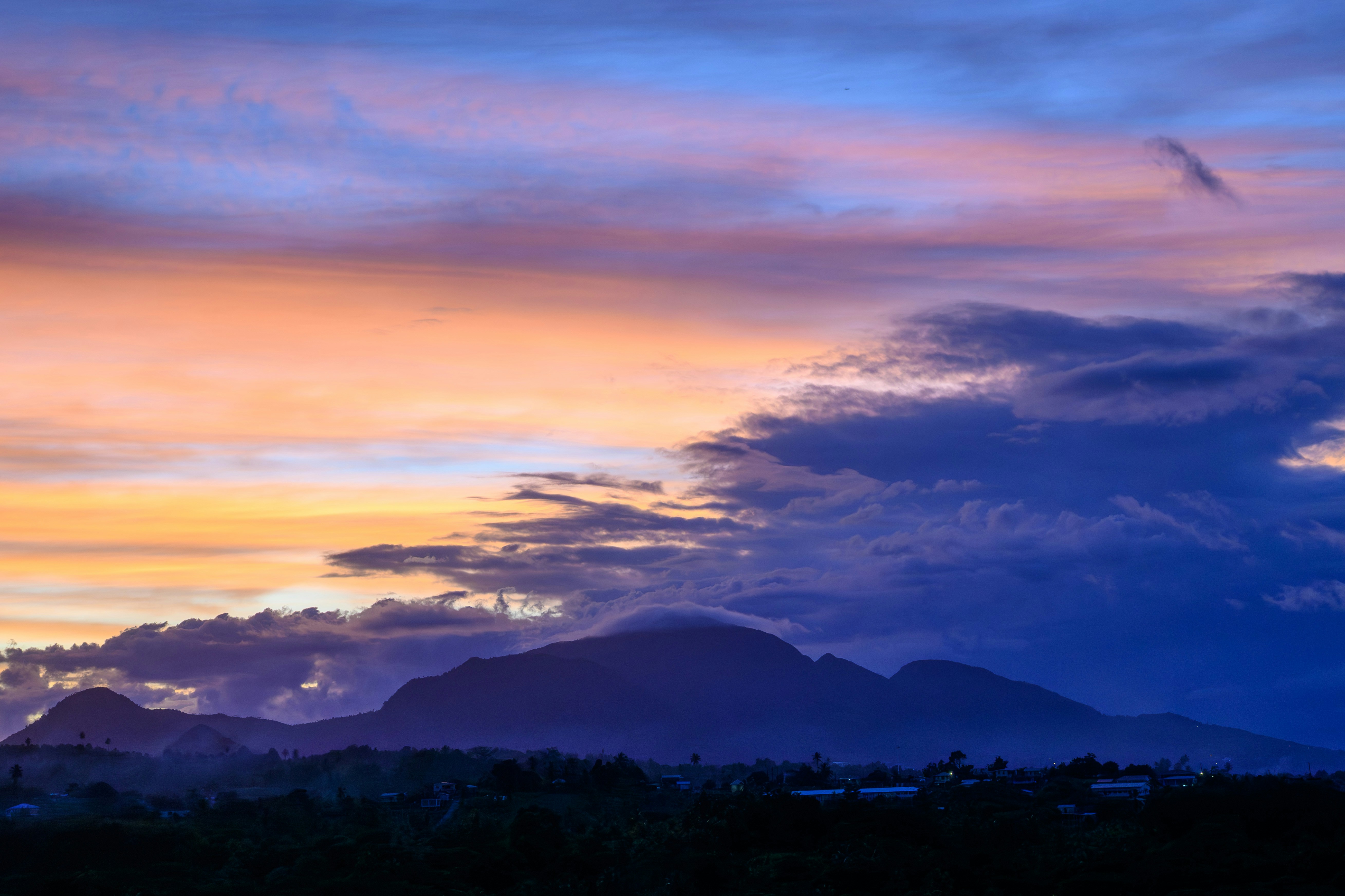 Vibrant sunset sky over dark mountain silhouettes.