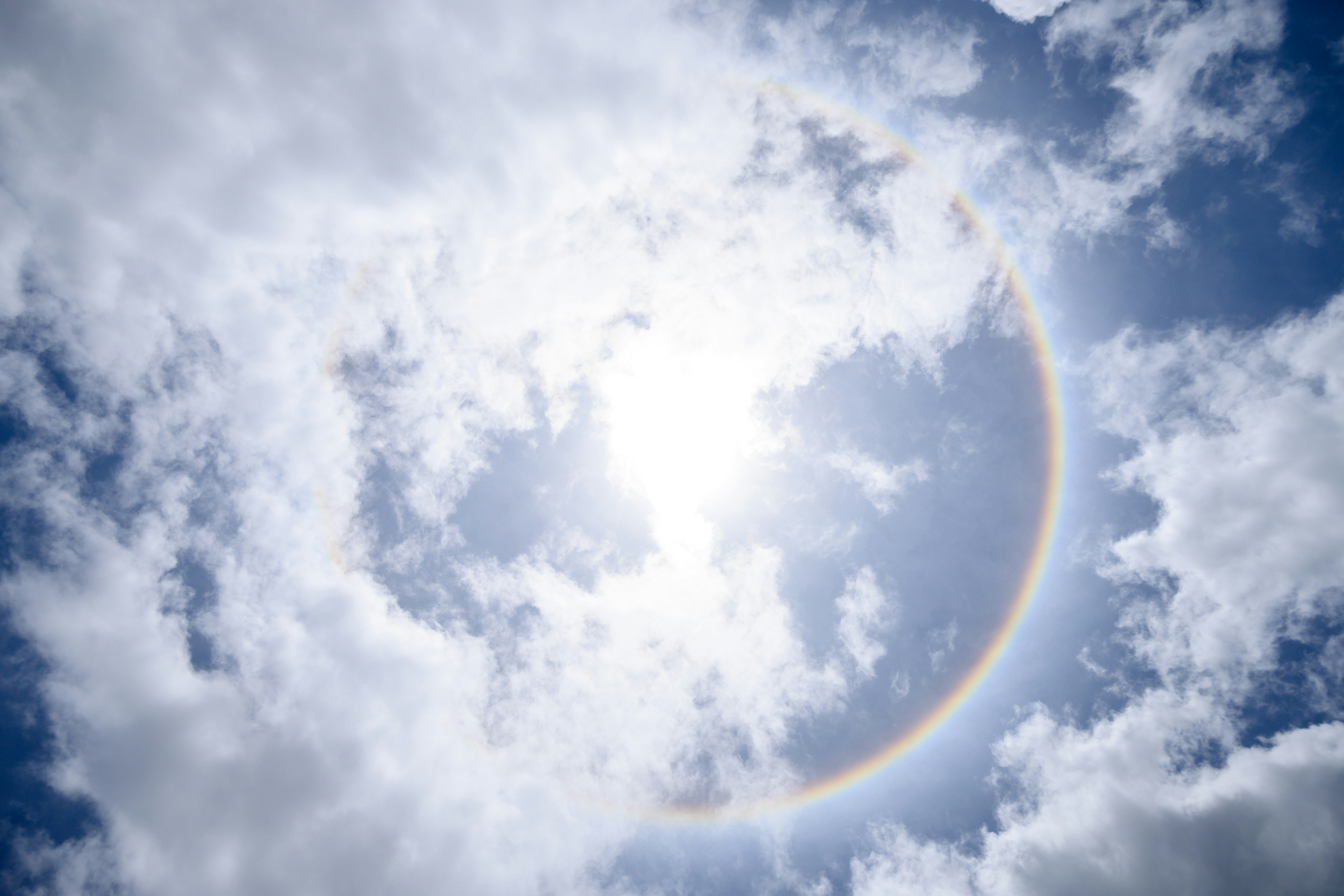 A bright sun halo appears in a cloudy blue sky.