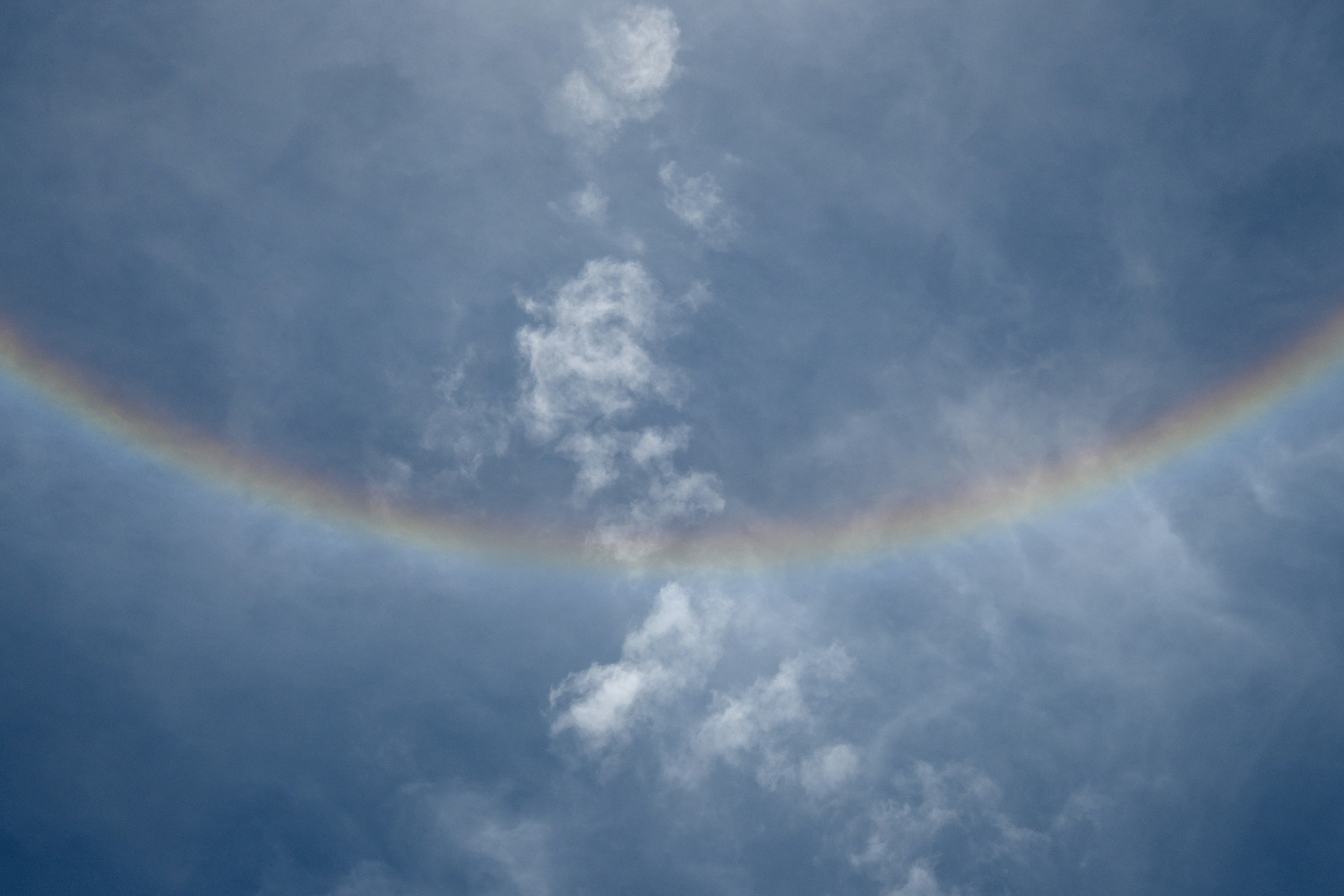Partial sun halo in a bright blue sky with clouds.