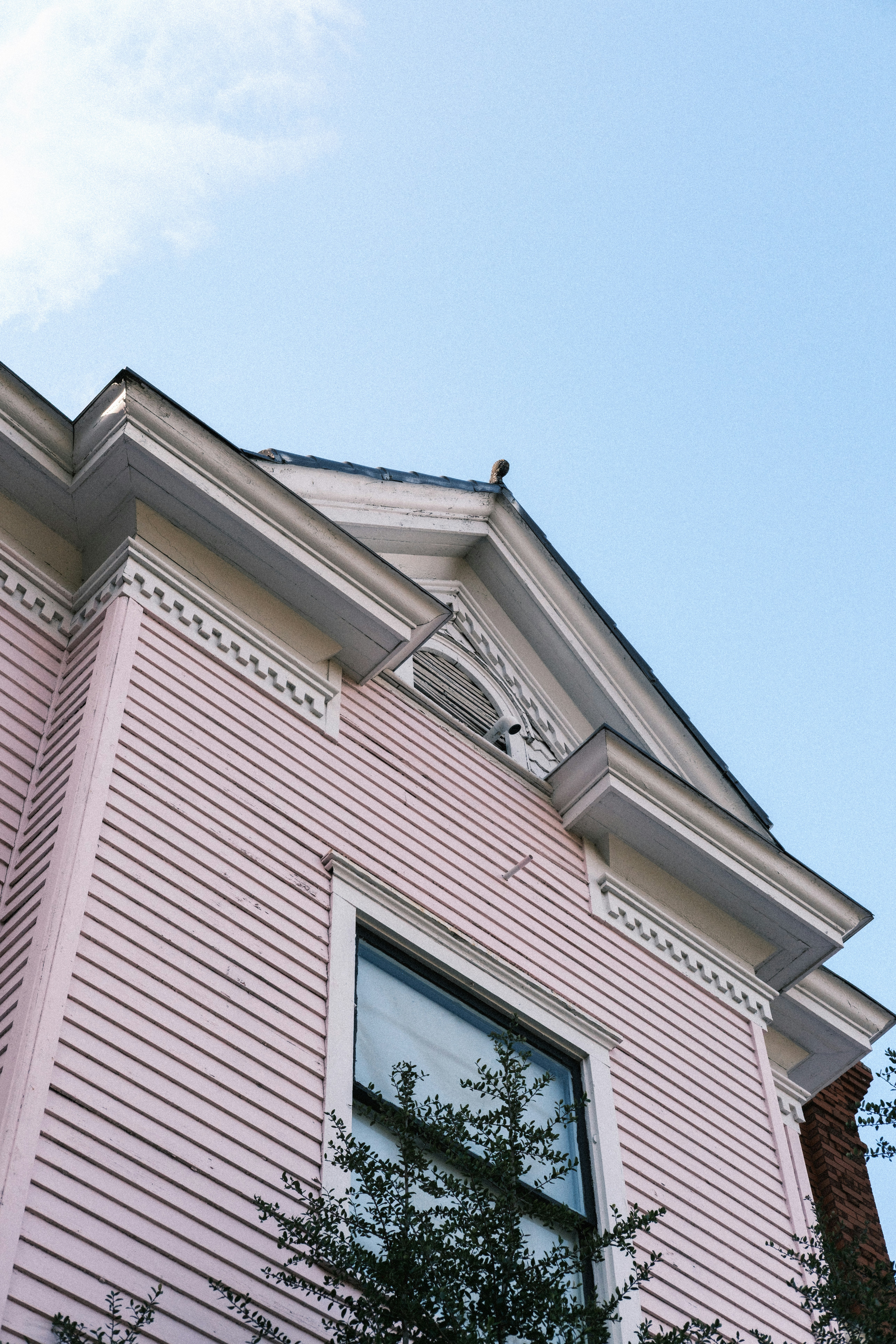 Pink Siding, Angular Rooflines: A Quiet Facade Under a Clear Sky