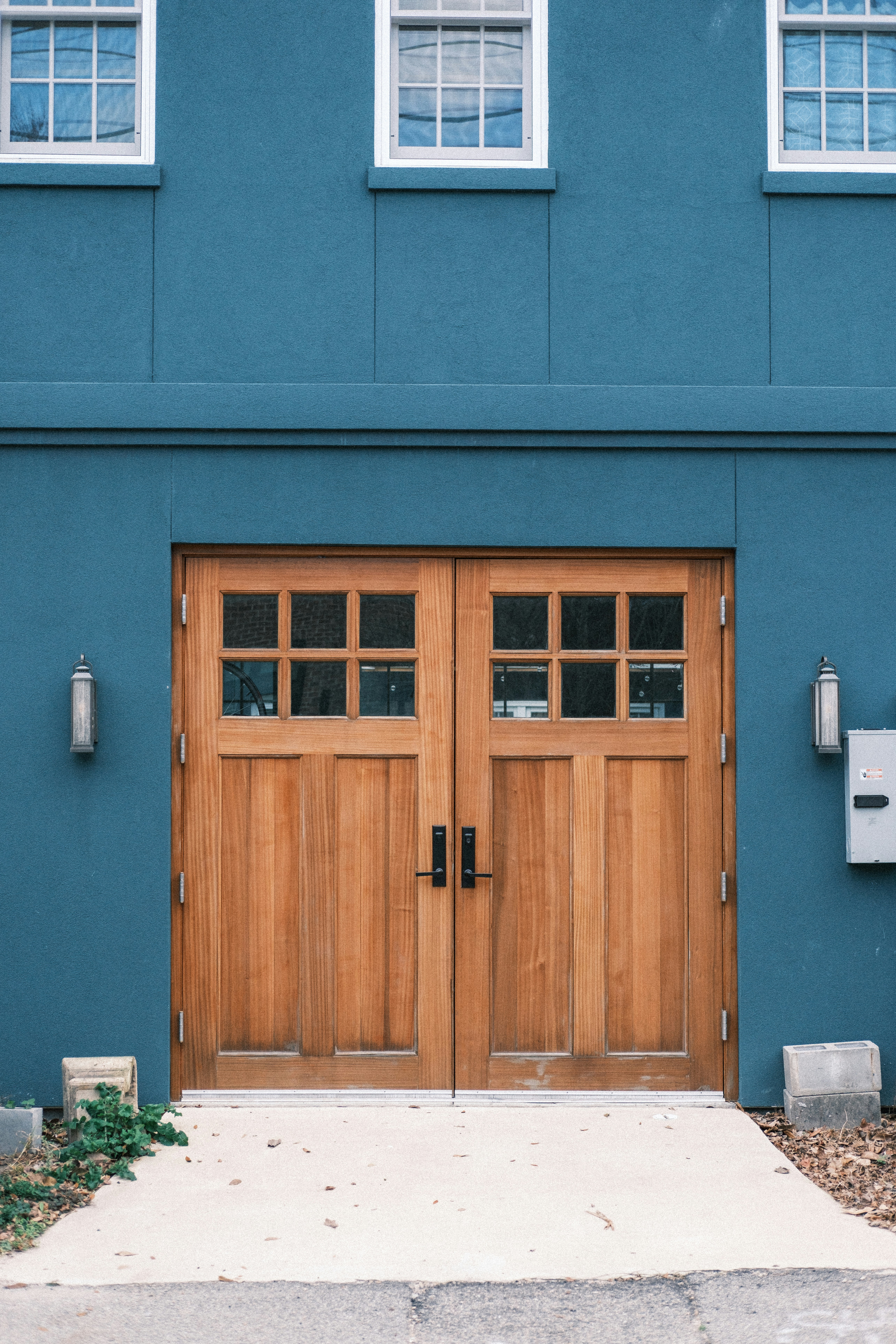 A blue building with two wooden doors and white windows.