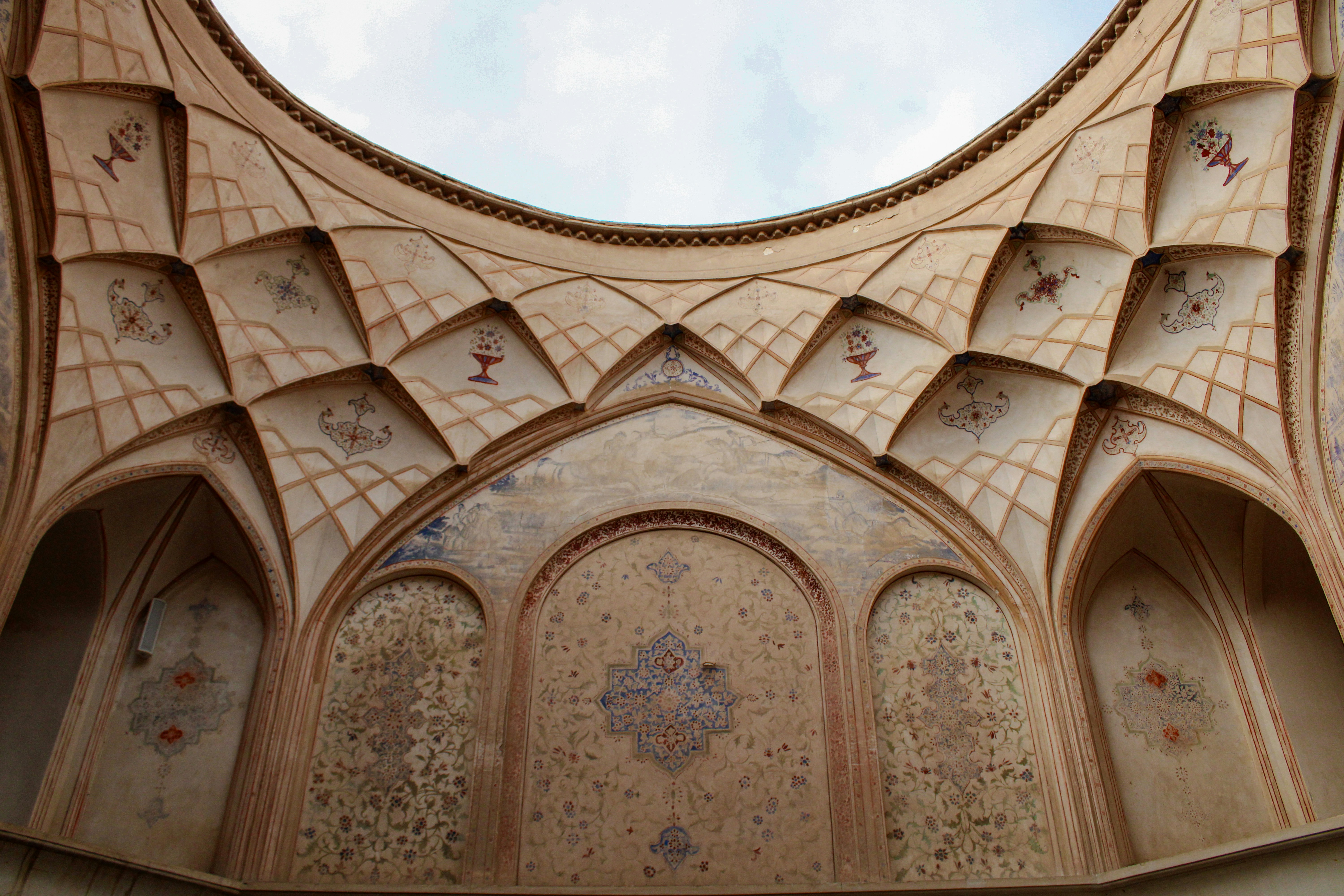 Ornate domed ceiling with intricate patterns and sky opening.