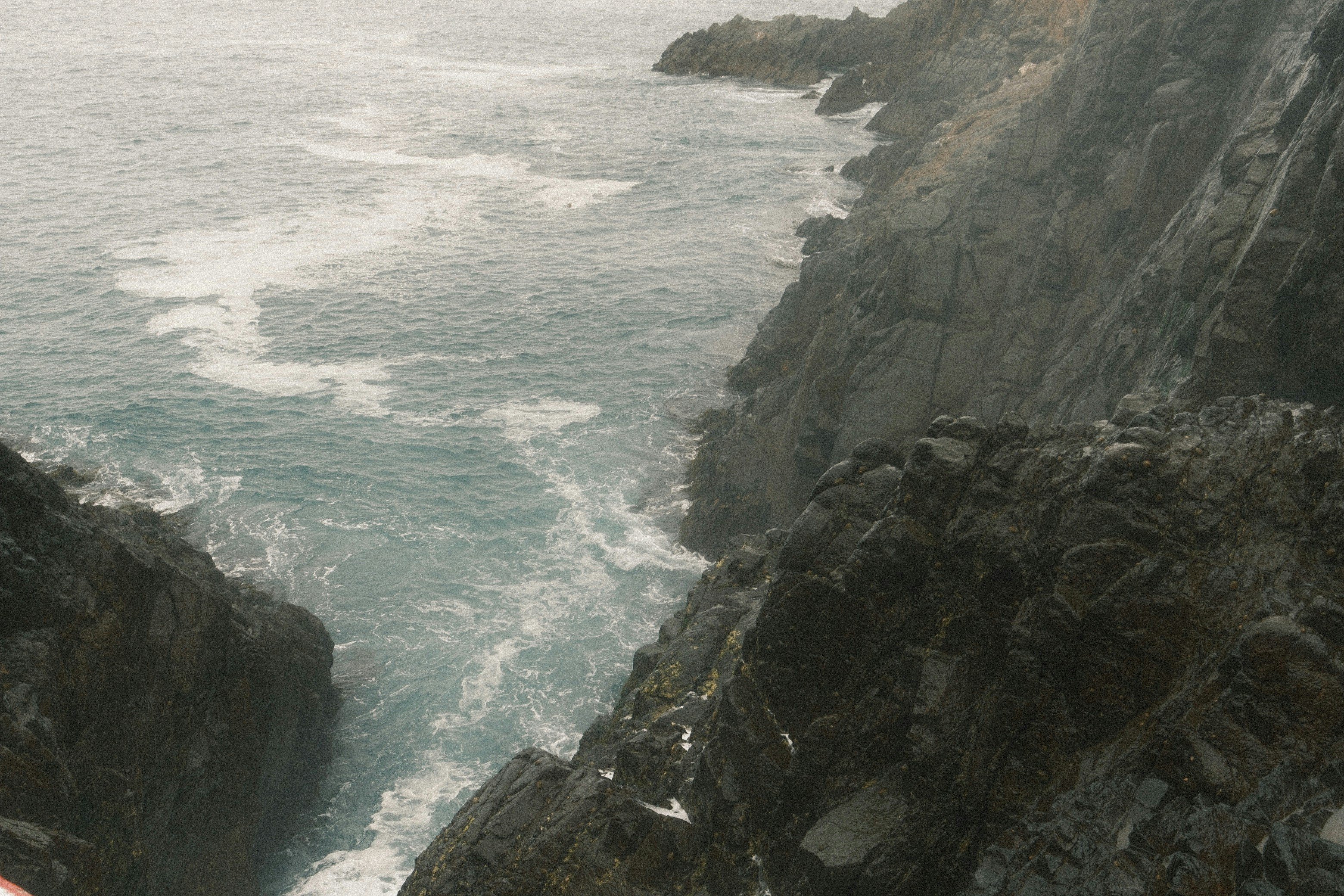 Waves crash against rugged dark cliffs along the coastline.