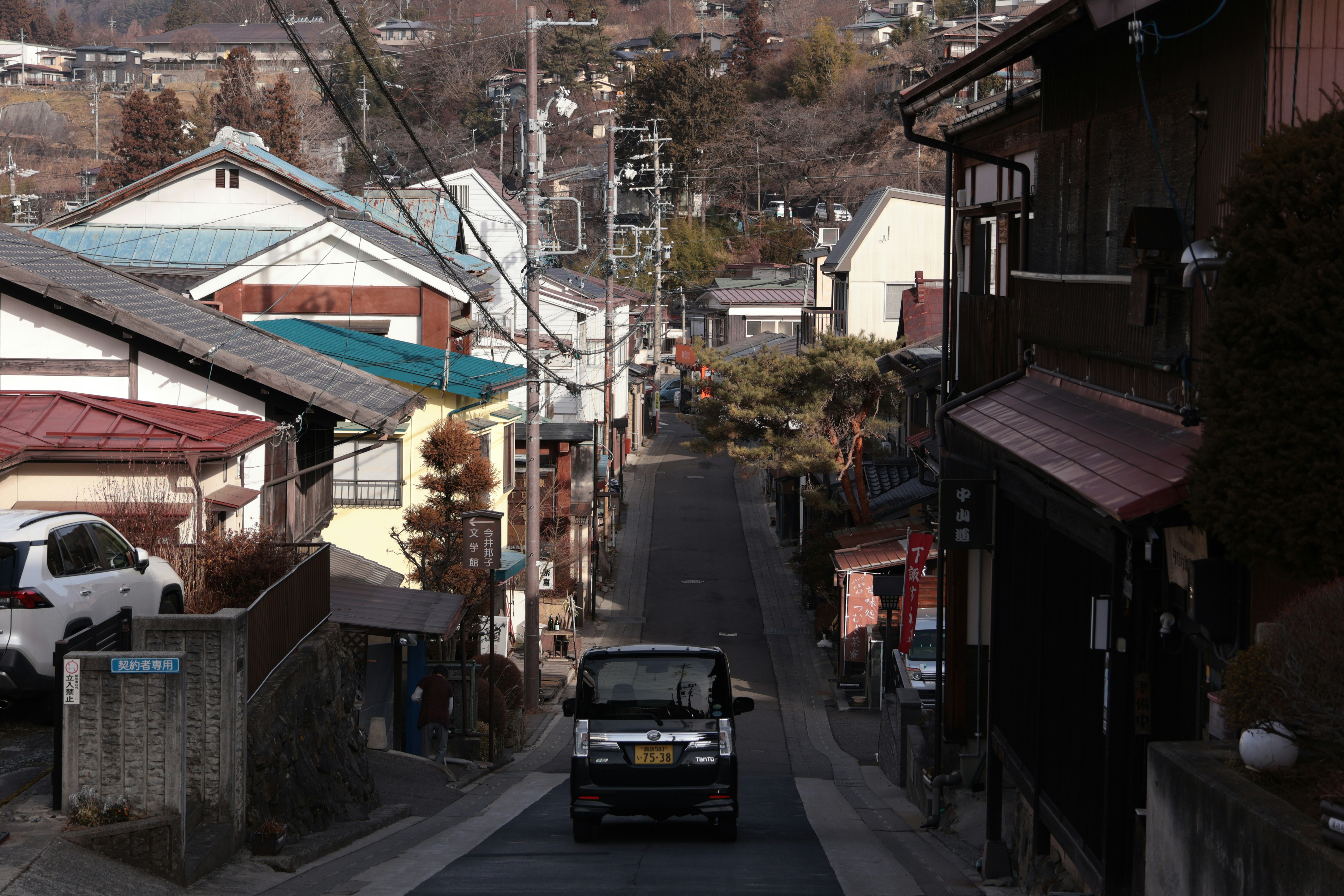 A Quiet Riverside Street: Car Down a Narrow Hill in a Traditional Town