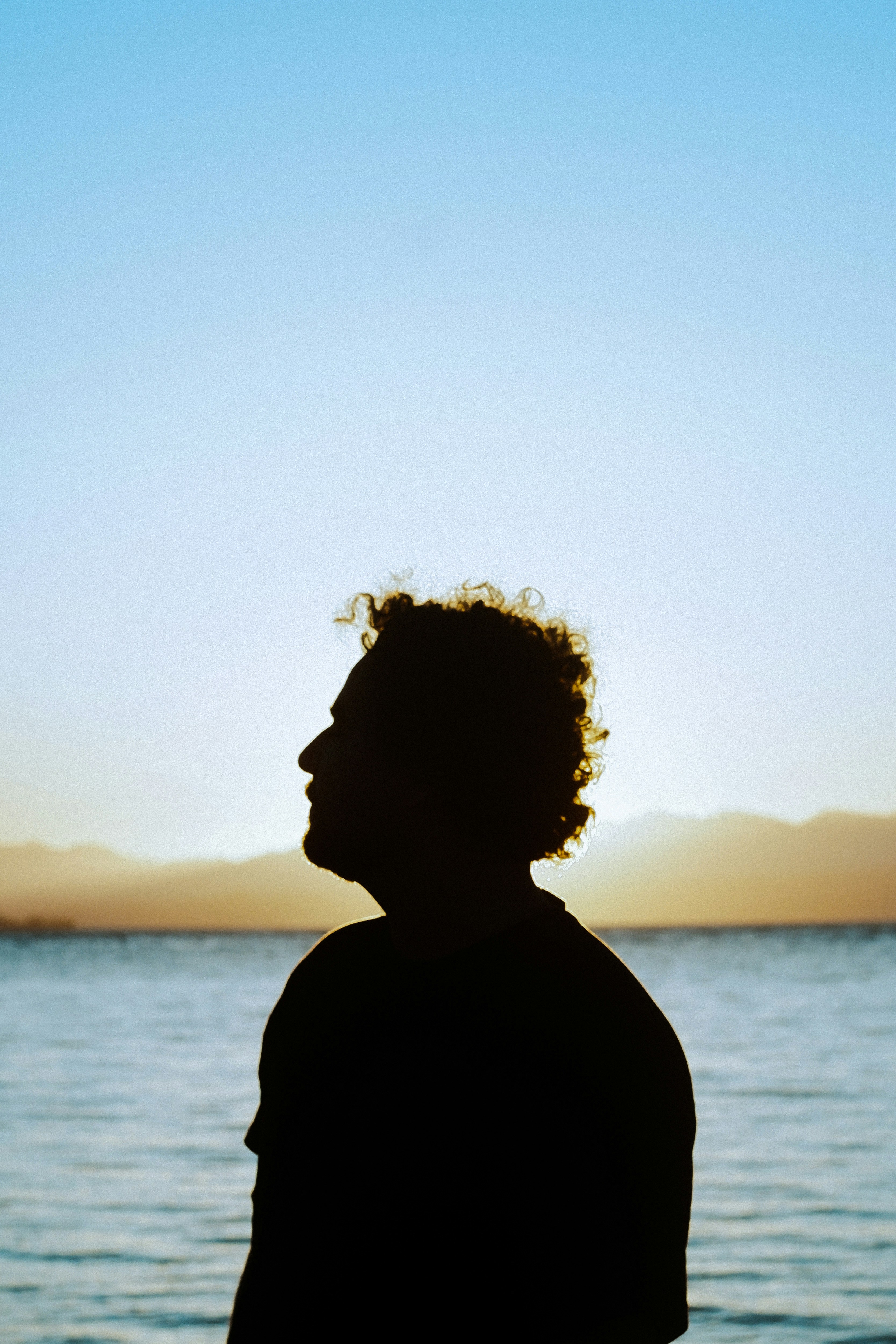 Silhouette at Dusk: Contemplative Profile Against a Calm Sea