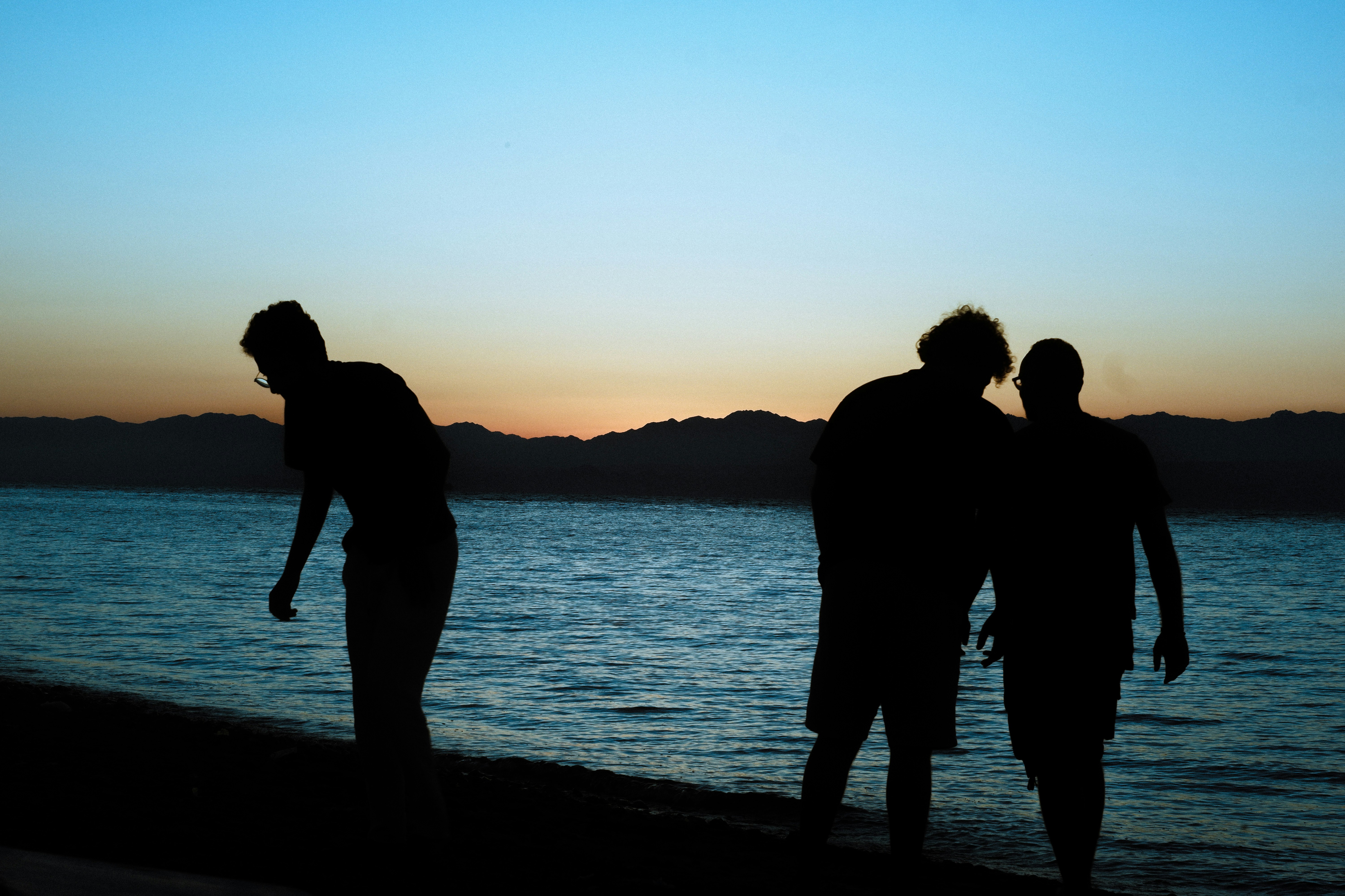 Sunset Silhouettes: A Trio Steps Toward the Water