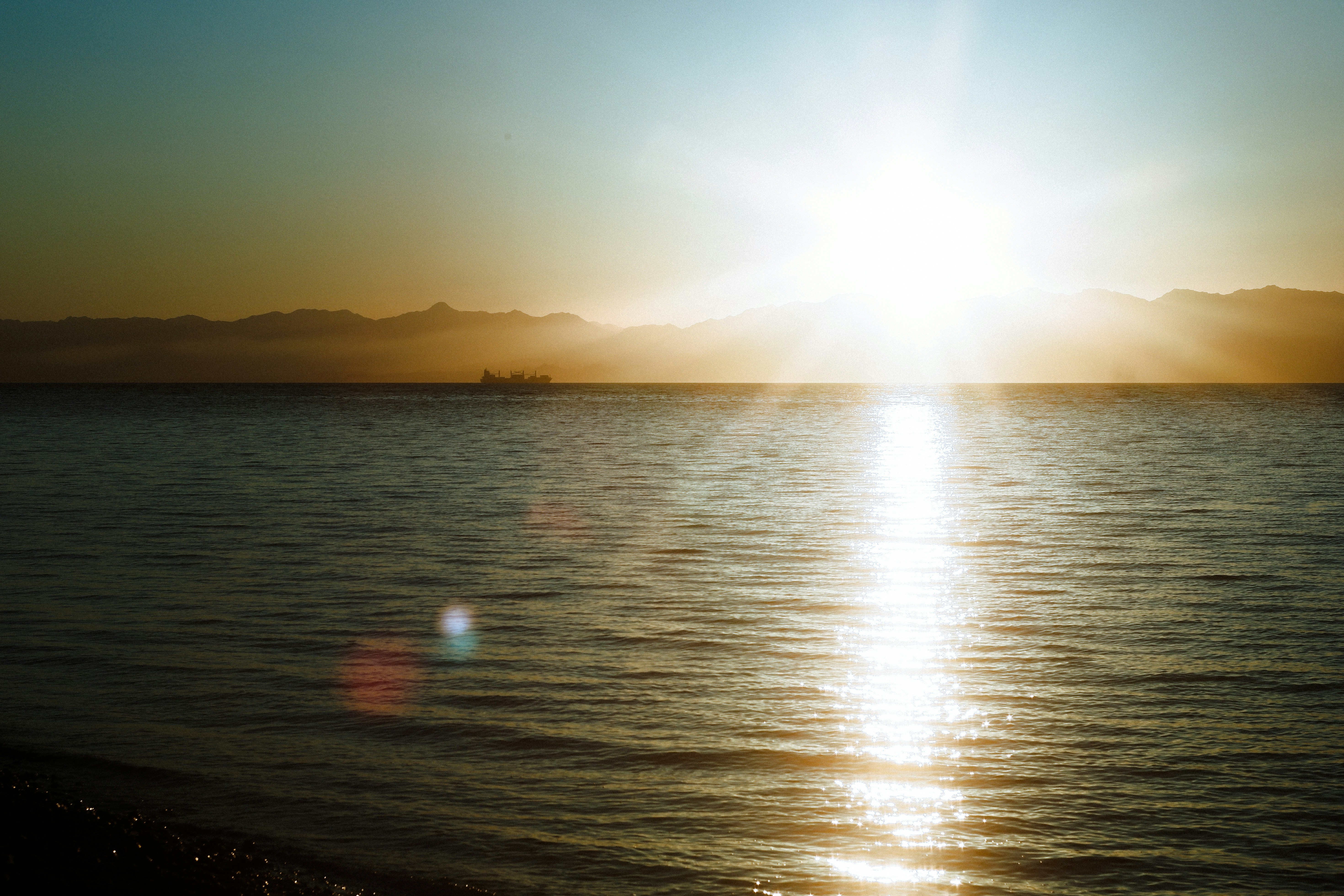 A blinding golden sun rising over the distant Sinai mountains, casting a brilliant trail of light across the sea