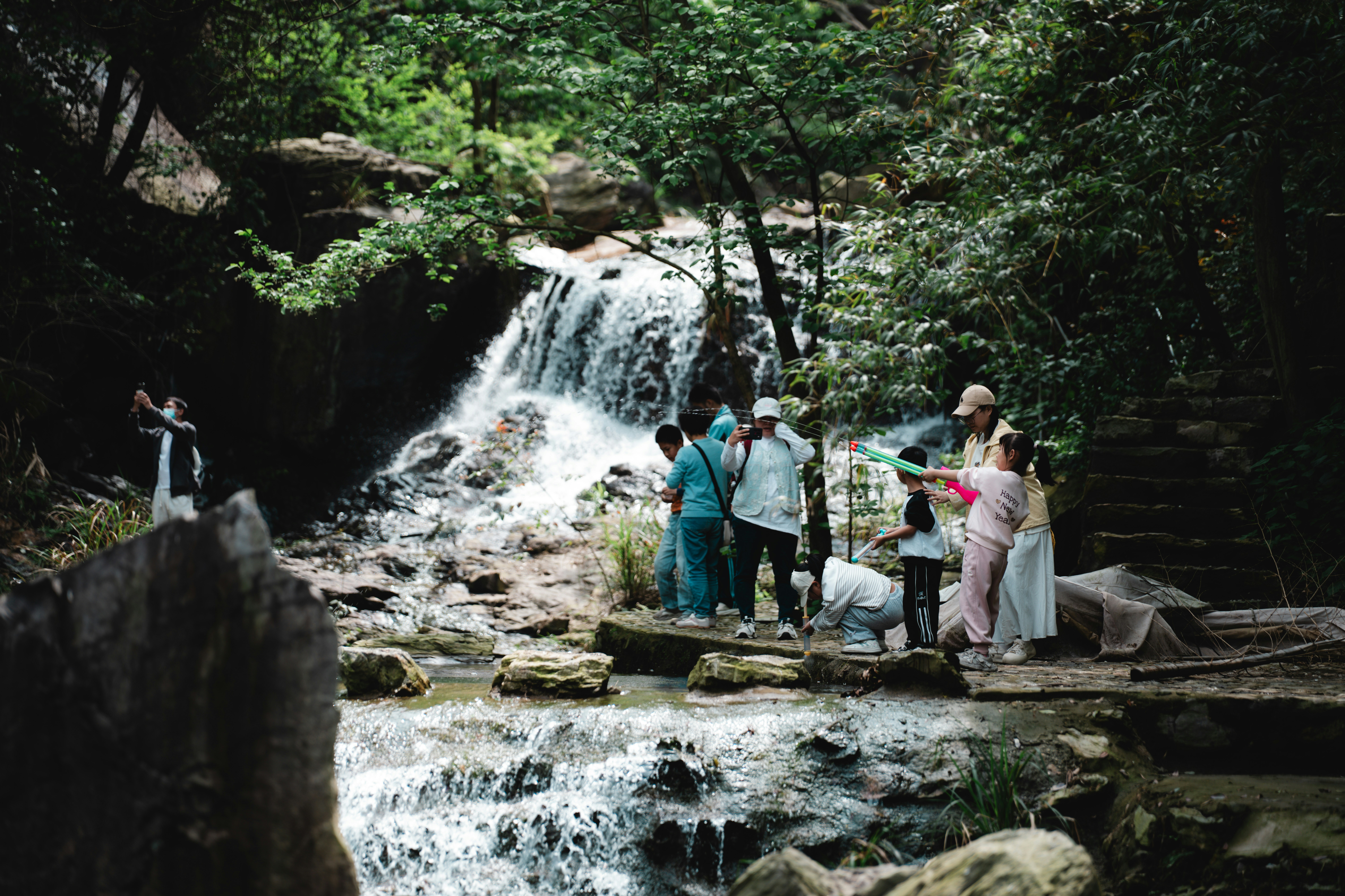 People gathered on a rocky ledge near a cascading waterfall