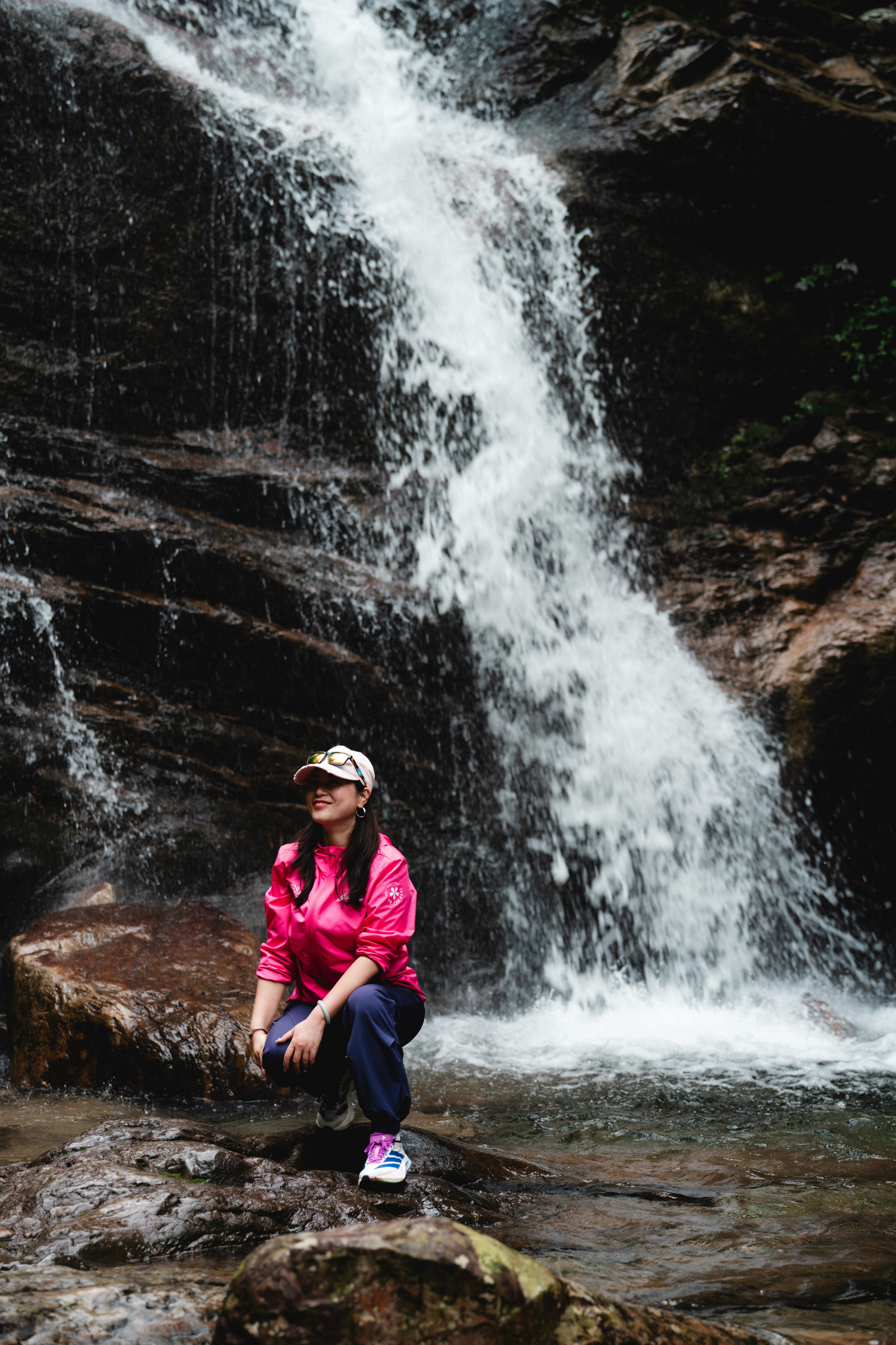 Pink-Jacketed Wanderer by a Cascading Curtain