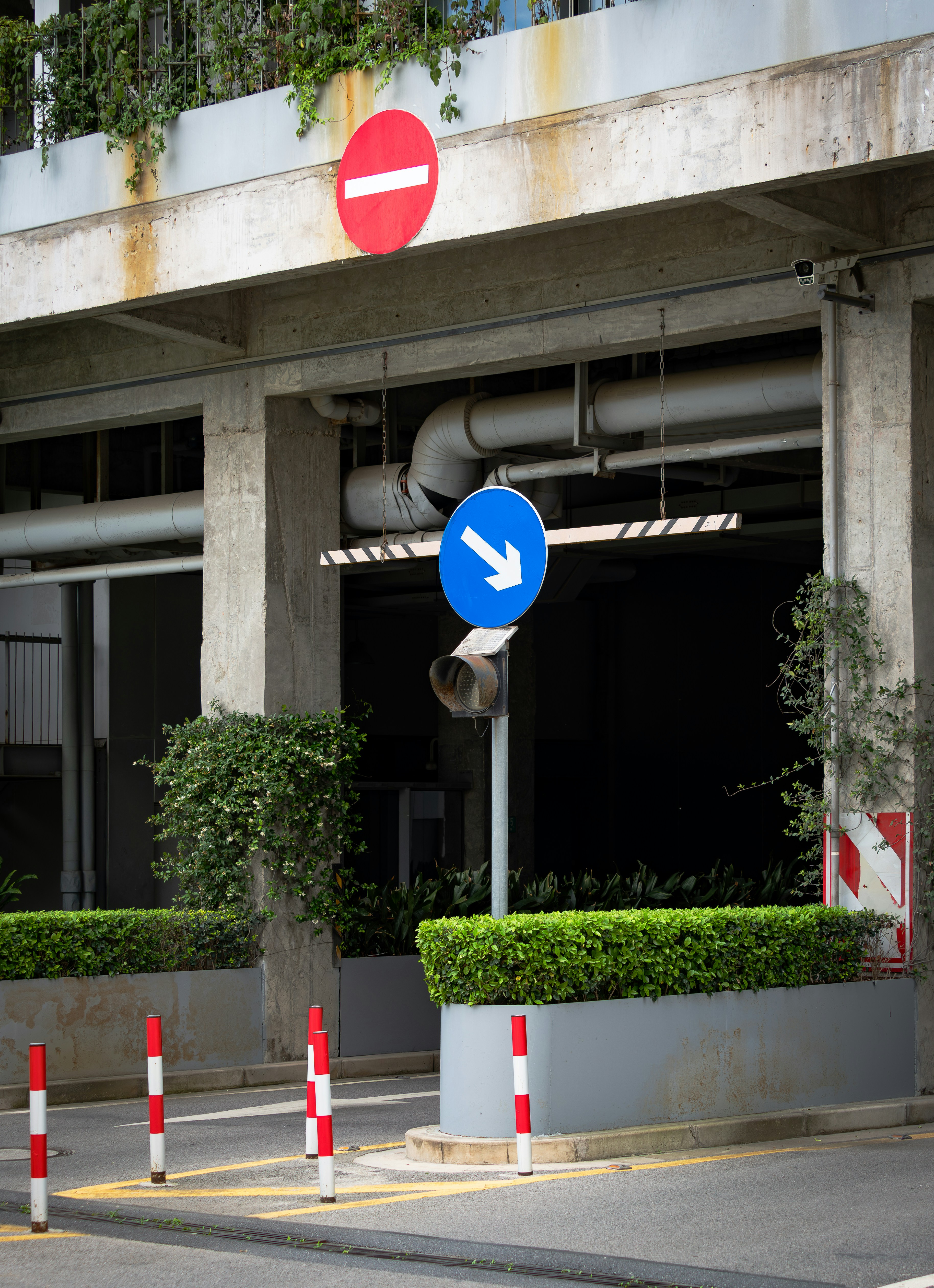 Concrete Underpass: A Red Sign Overhangs a Blue Arrow in Urban Geometry