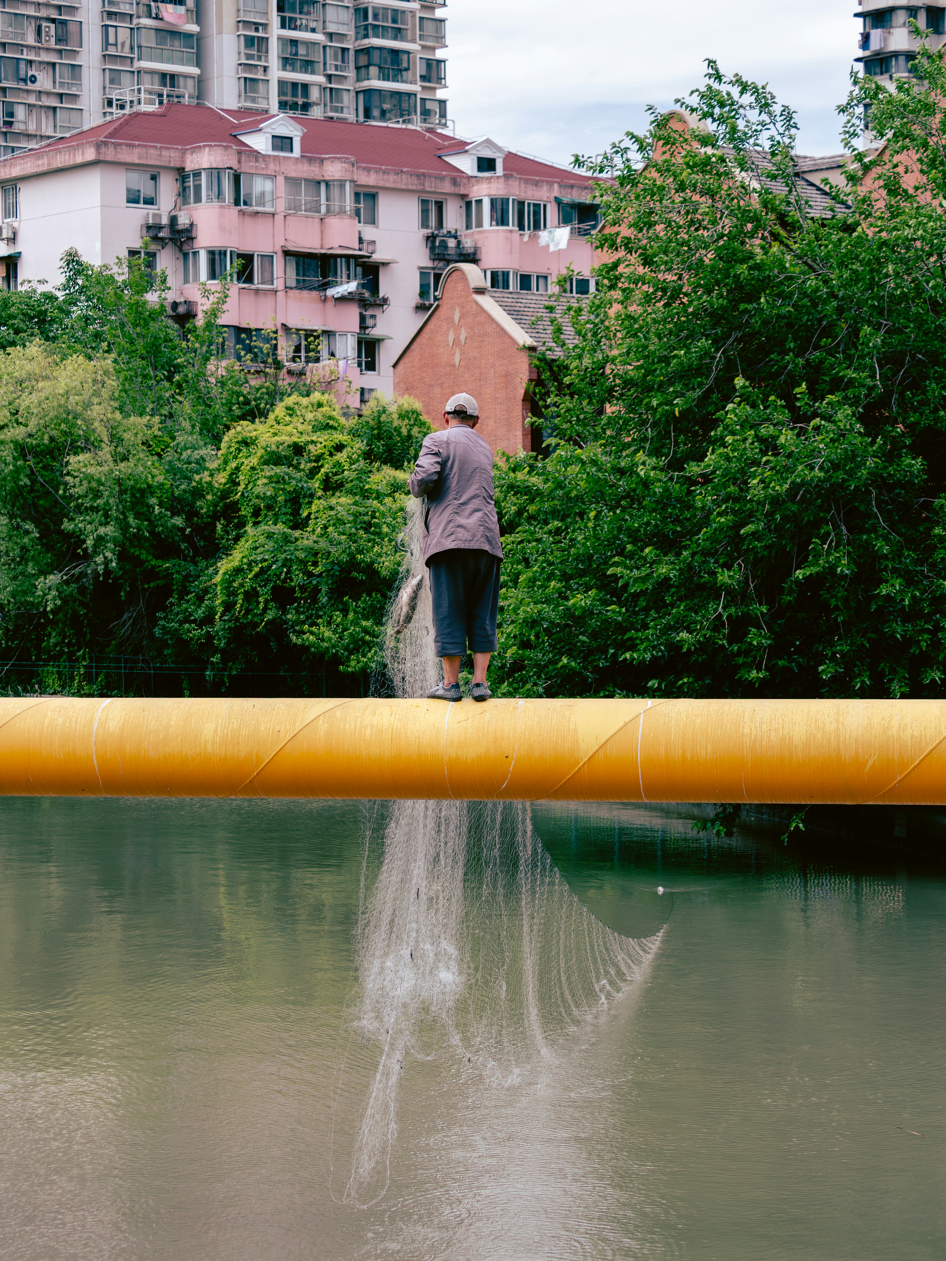Floating over the yellow canal: a passerby on the pipe against a city backdrop