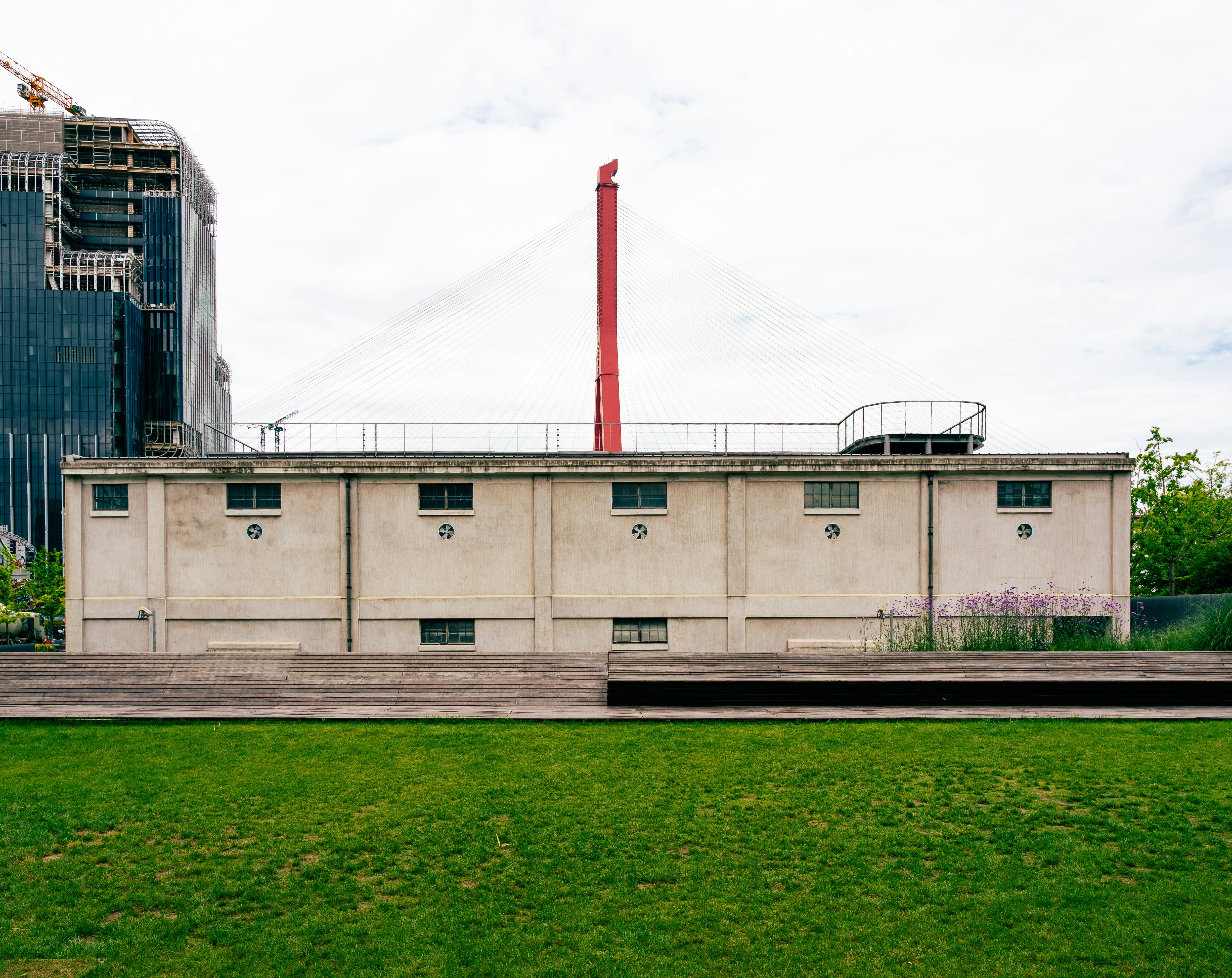 A concrete building with a red tower and green grass.